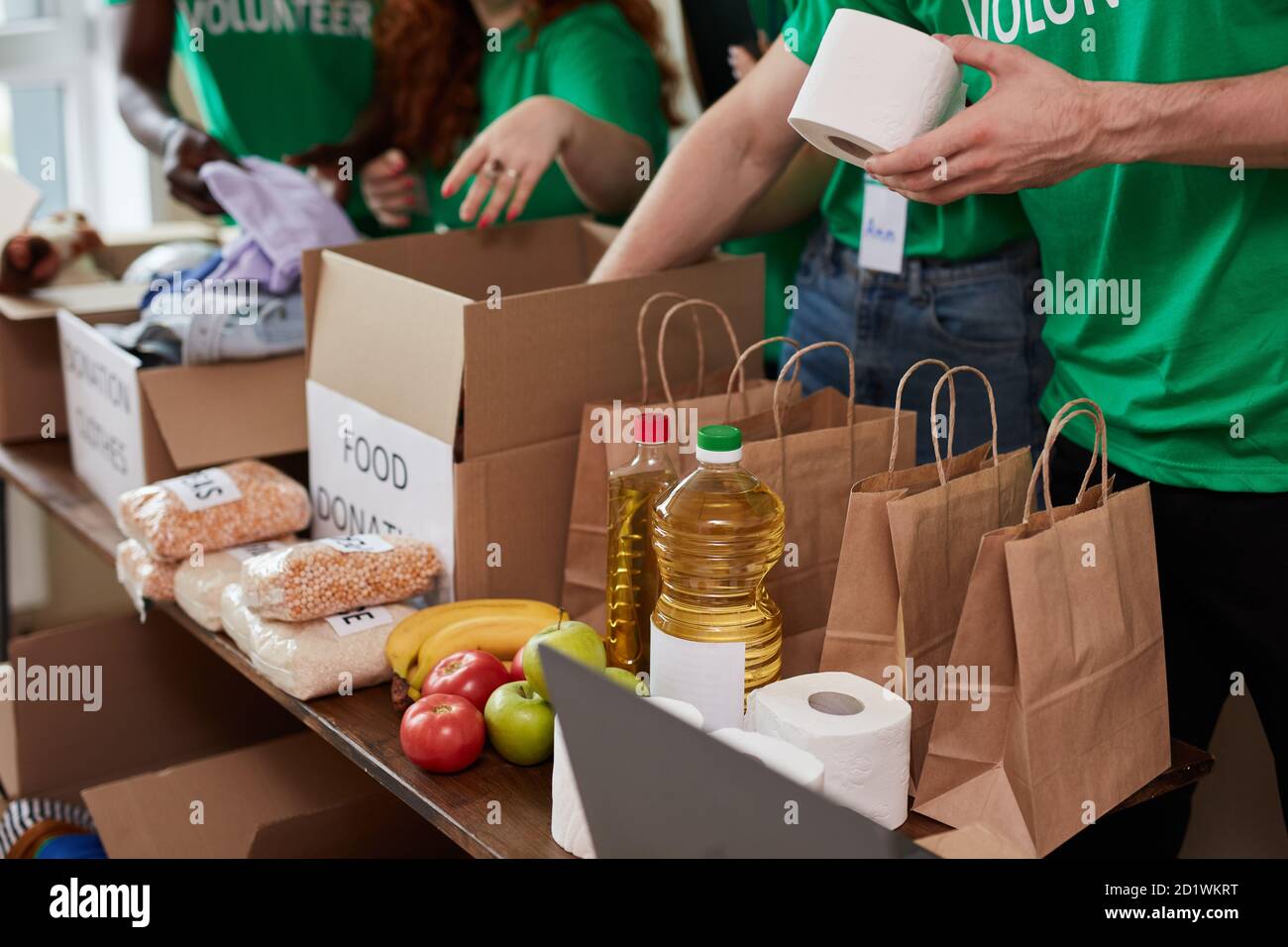 group of diverse people sort through donated food items while ...