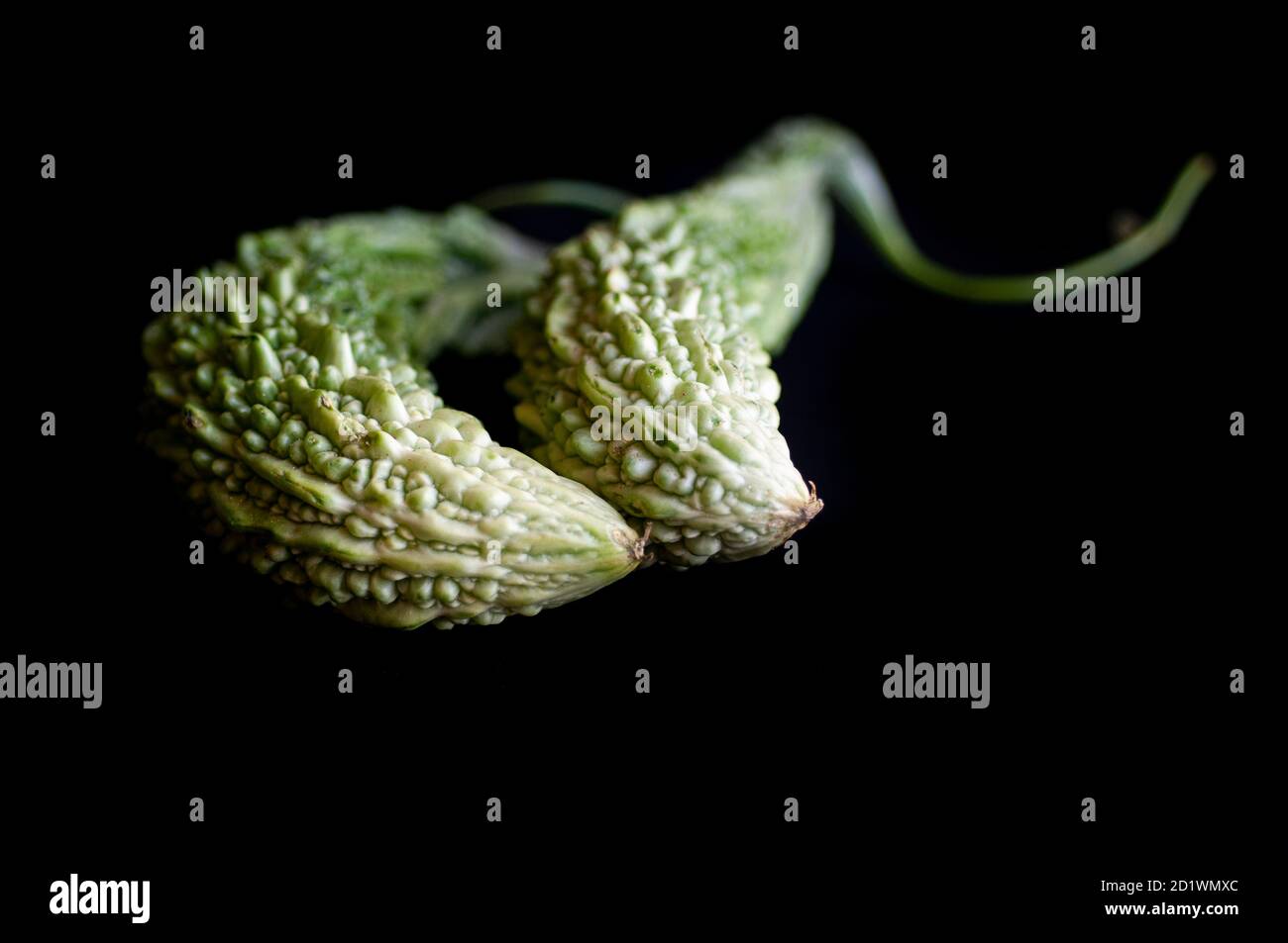 Bitter gourd vegetables on a plain black background Stock Photo - Alamy