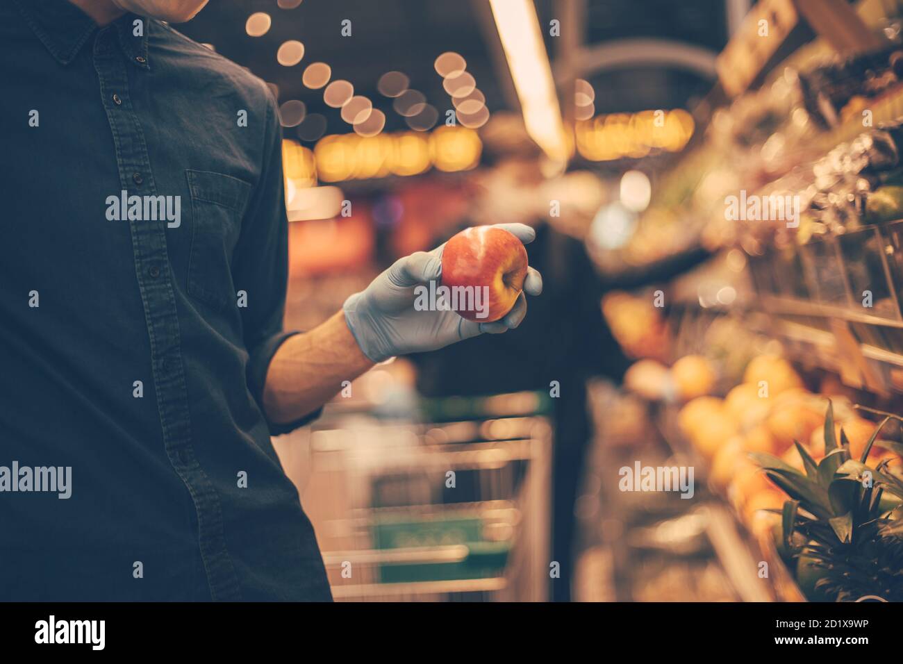 man in a protective mask when selecting apples at the supermarket Stock ...