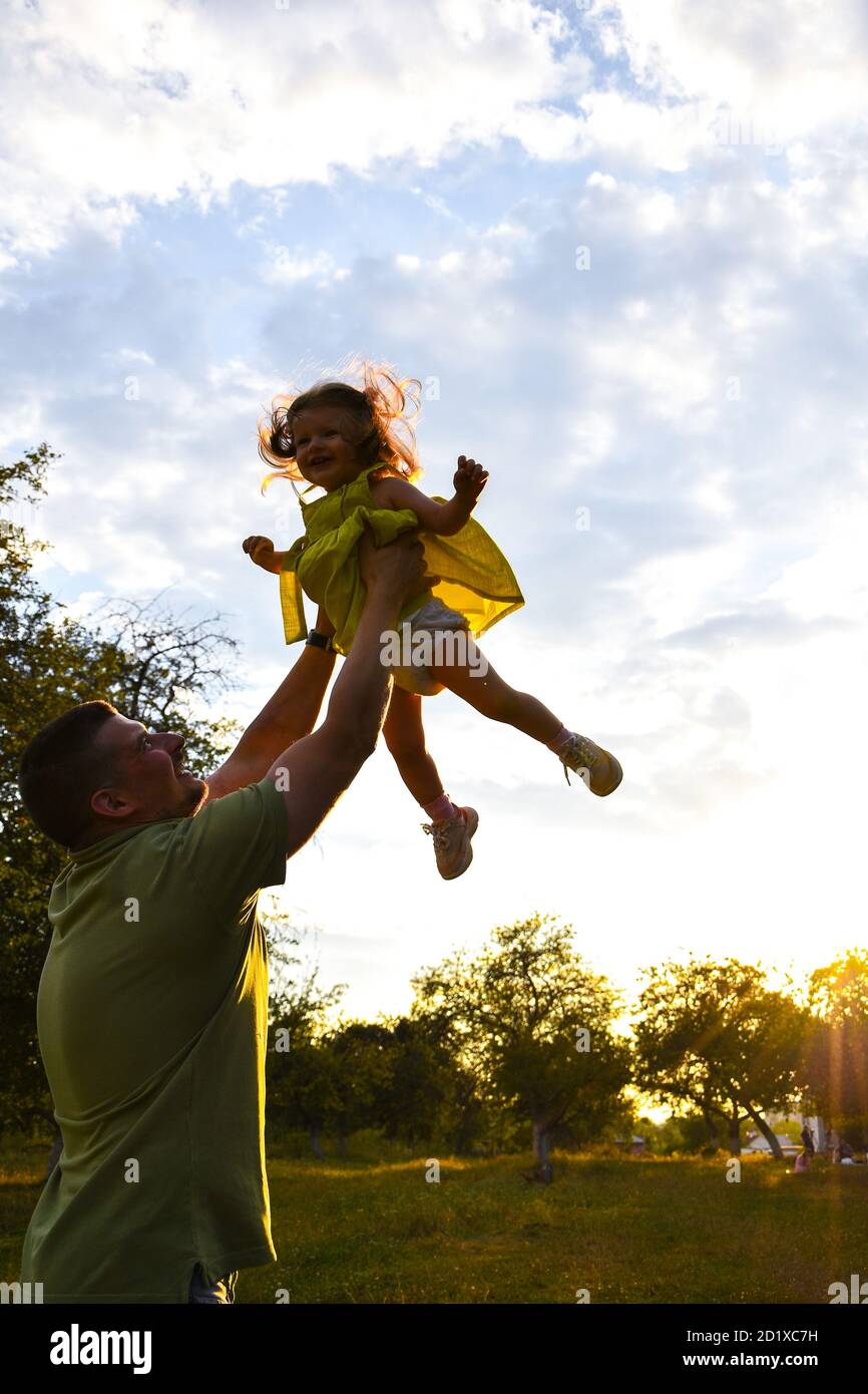 Adorable little happy screaming girl being thrown up in the air by her ...