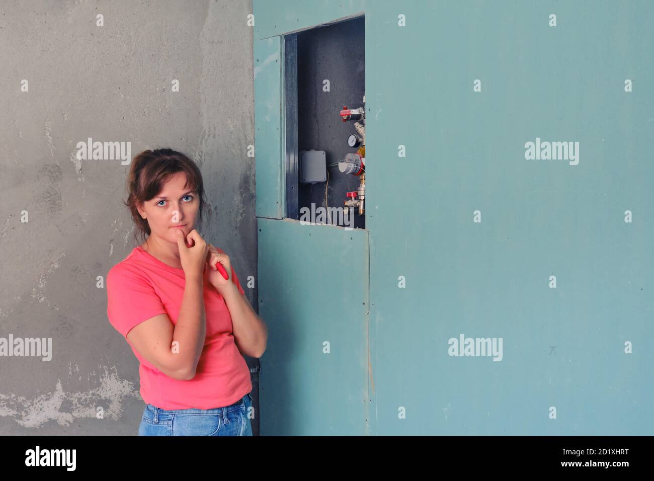 A woman stands beside the water pipes, thinking. Repair of pipelines ...