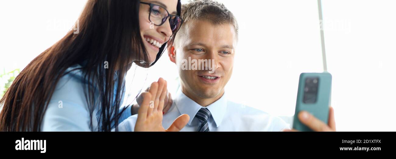 Work colleagues hold smartphone and communicate with their ...