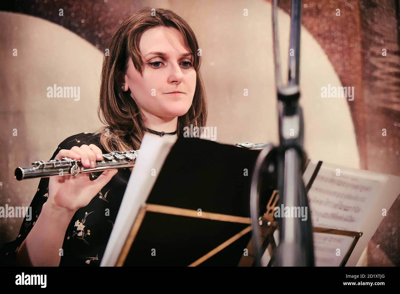 The flutist looks at the notes. Woman on stage with a flute. The ...