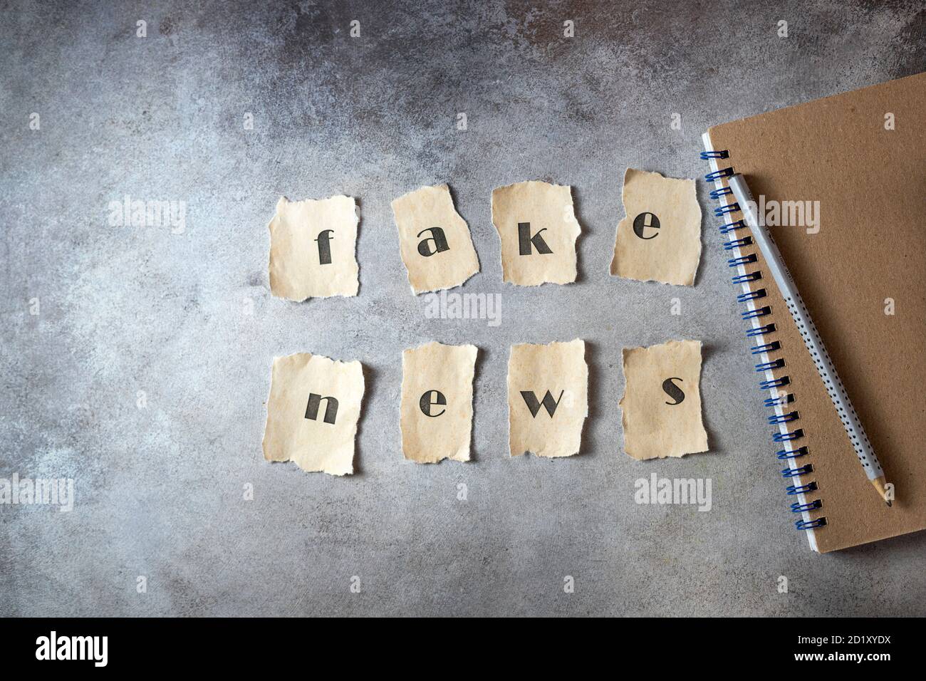 Fake news concept, letters written on old paper, on gray concrete ...