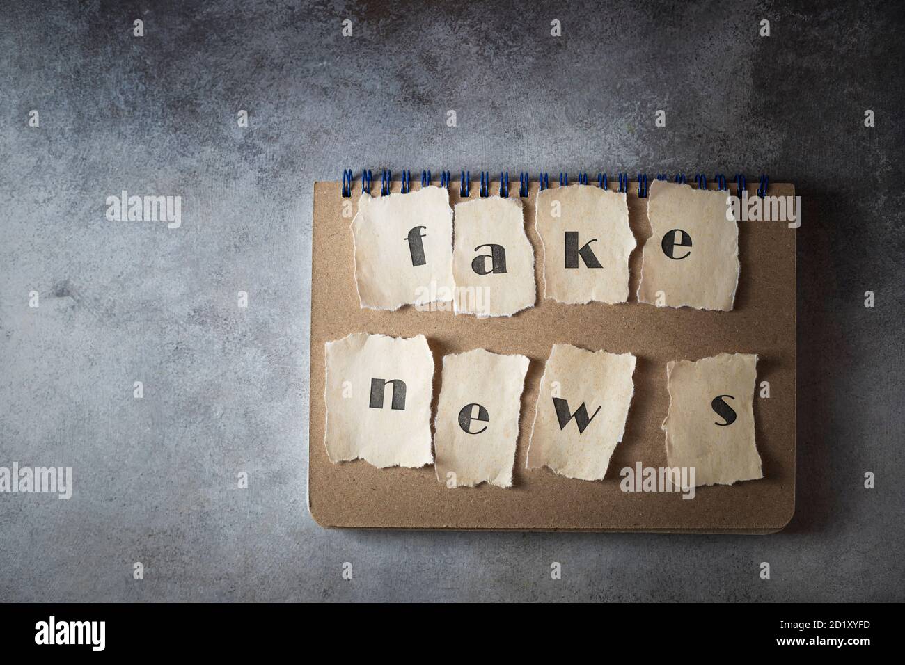 Fake news concept, letters written on old paper, on gray concrete ...