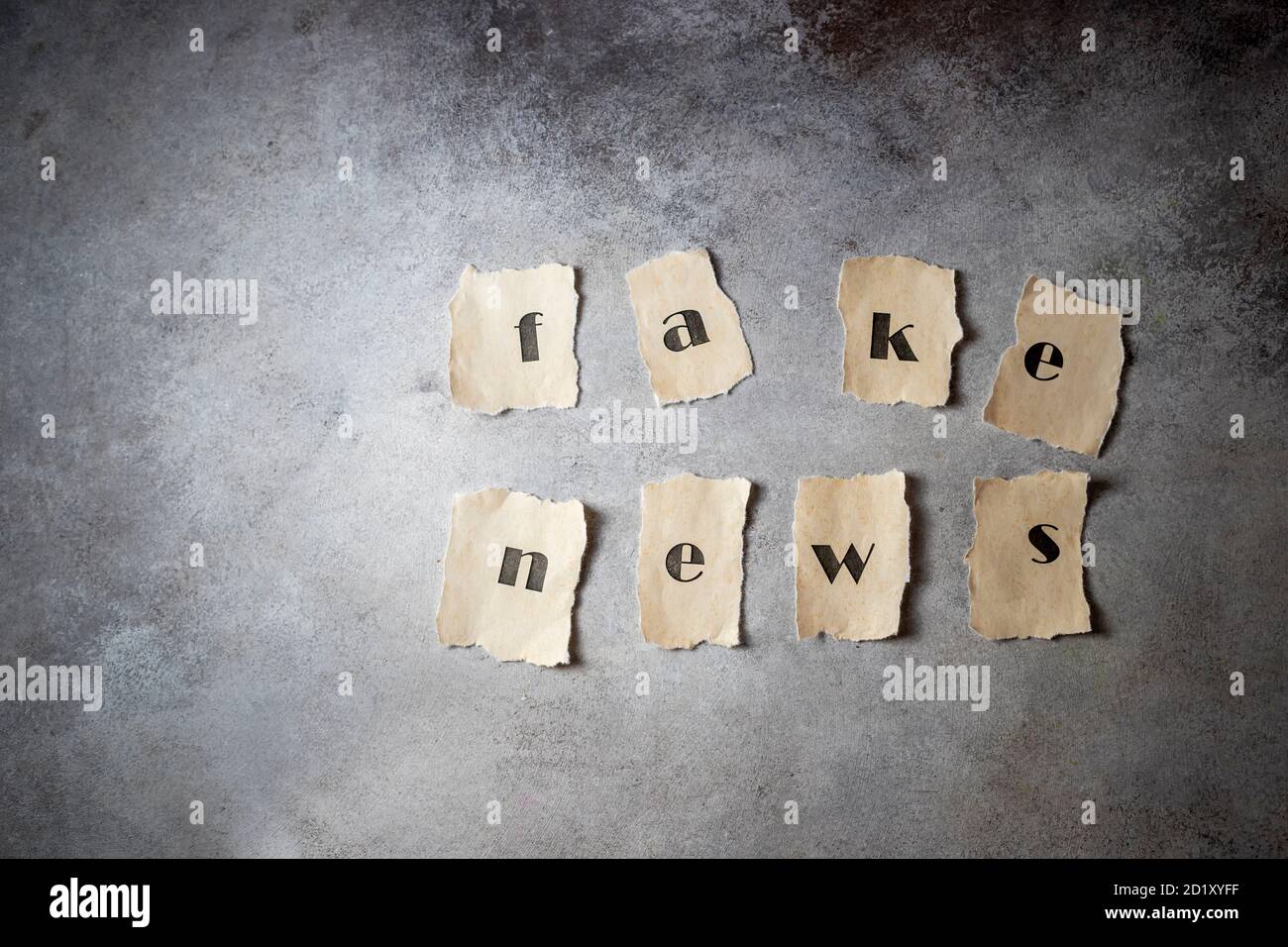 Fake news concept, letters written on old paper, on gray concrete ...