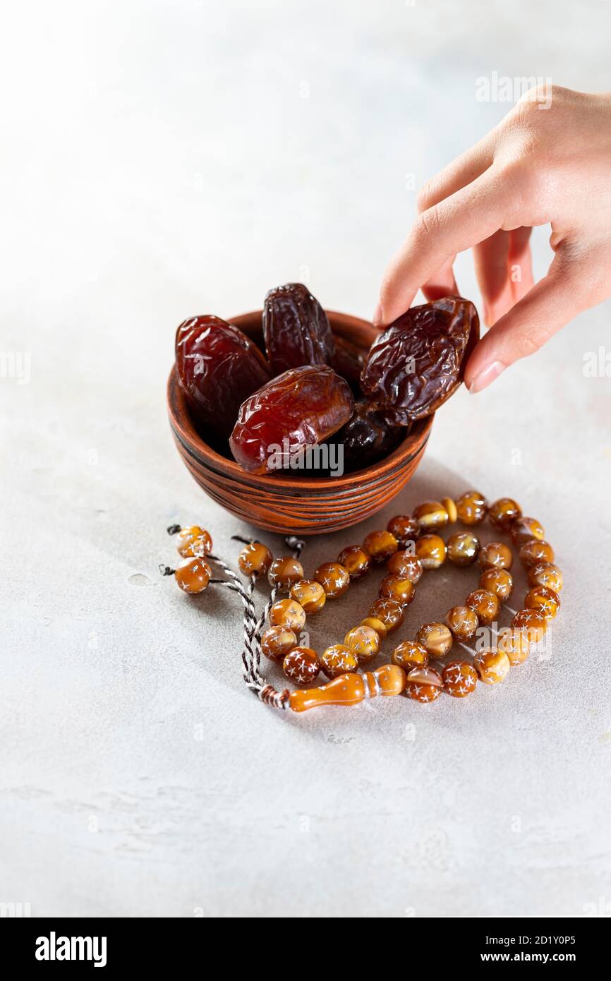 Plate with dates, decorative arabic lantern and rosary on a light ...