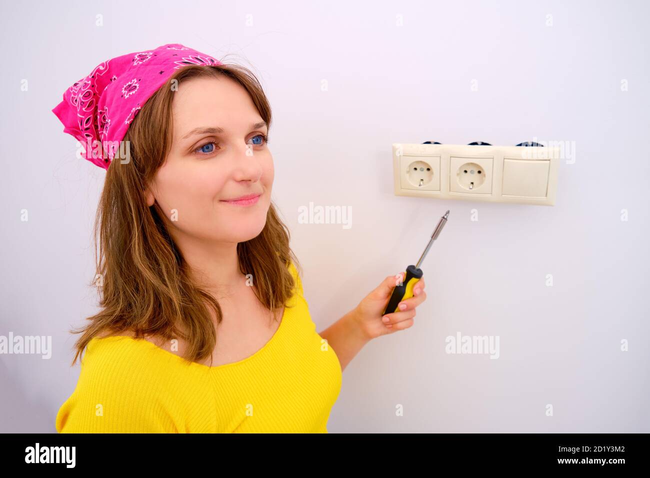 Smiling girl holding a screwdriver in her hands to repair electrical ...
