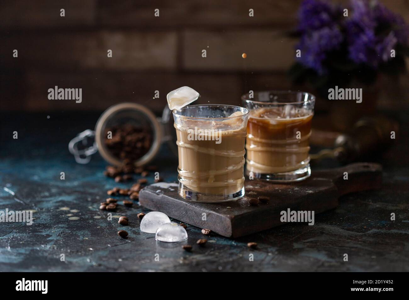 Splash of iced coffee in a glass glass and coffee beans on a brown ...