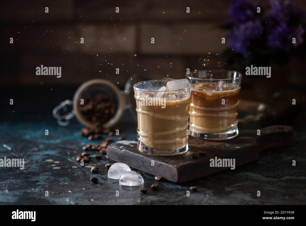 Splash of iced coffee in a glass glass and coffee beans on a brown ...