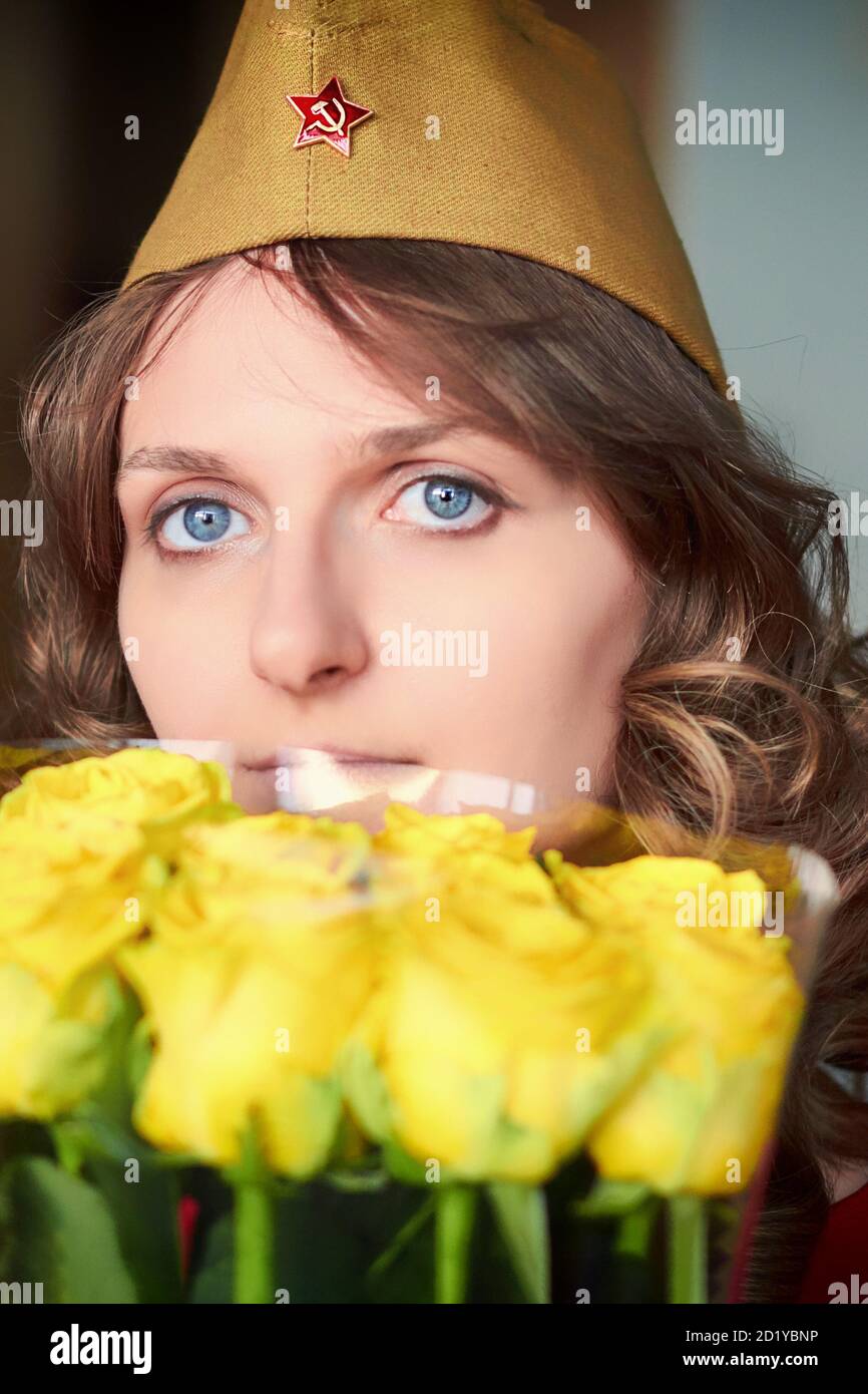 A young woman with flowers at the victory festival. Girl in uniform of ...