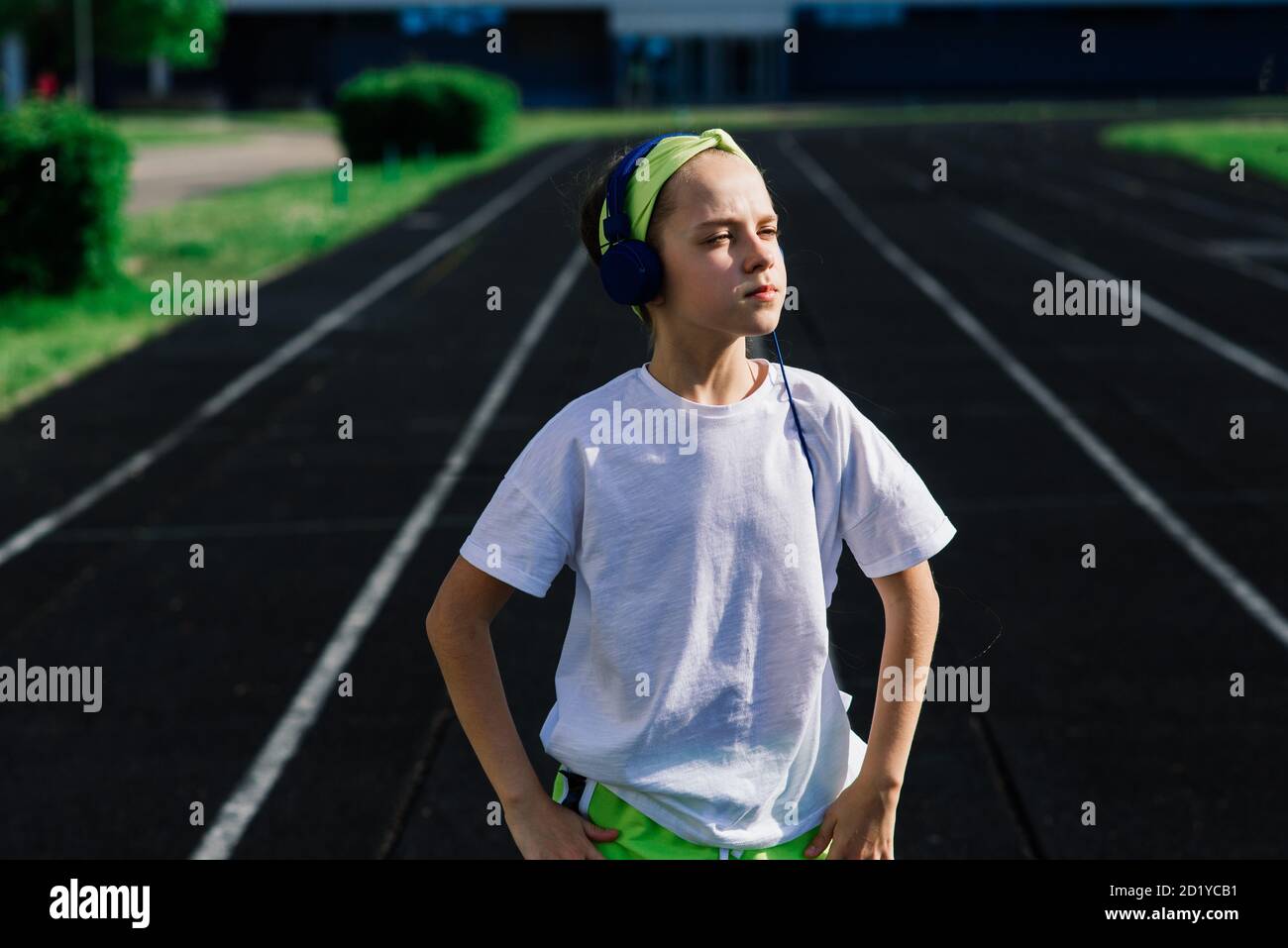 Girl jogging on a sunny summer evening, laying on treadmill, stadium ...