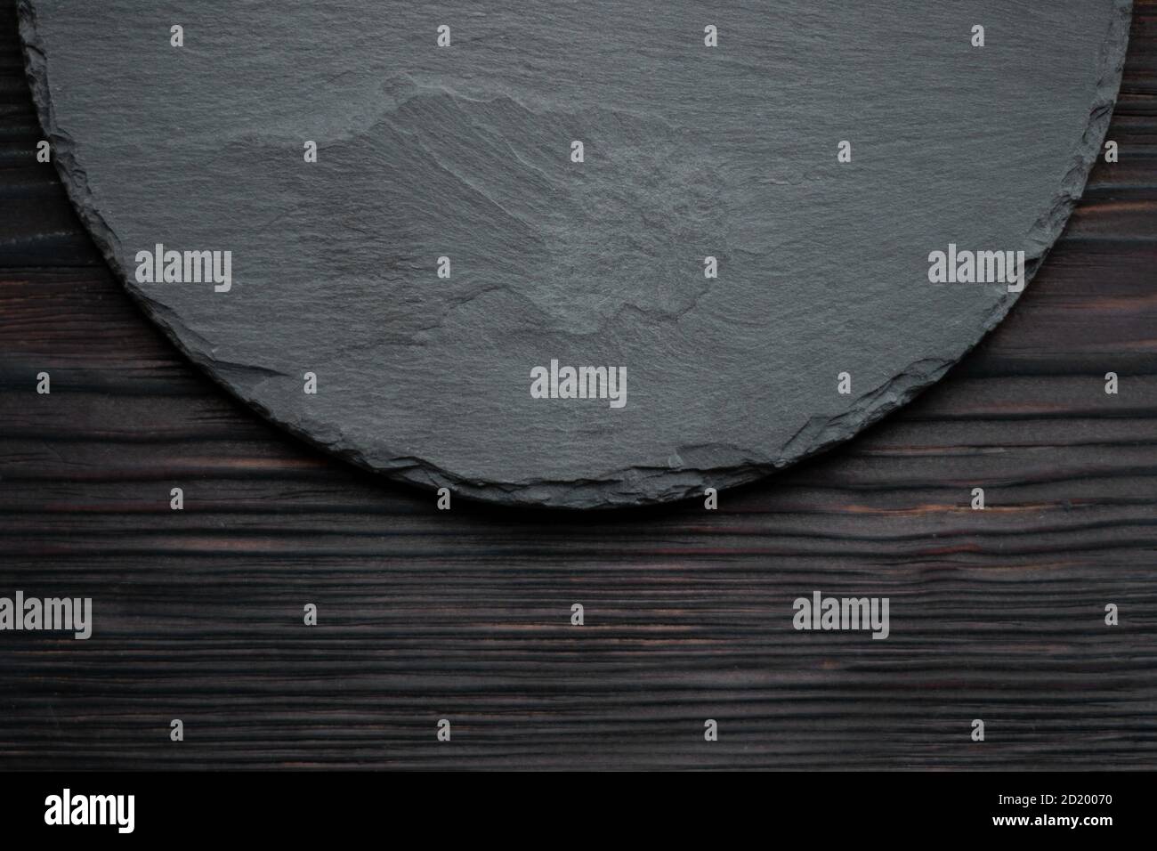 round black slate board on dark wooden table Stock Photo - Alamy