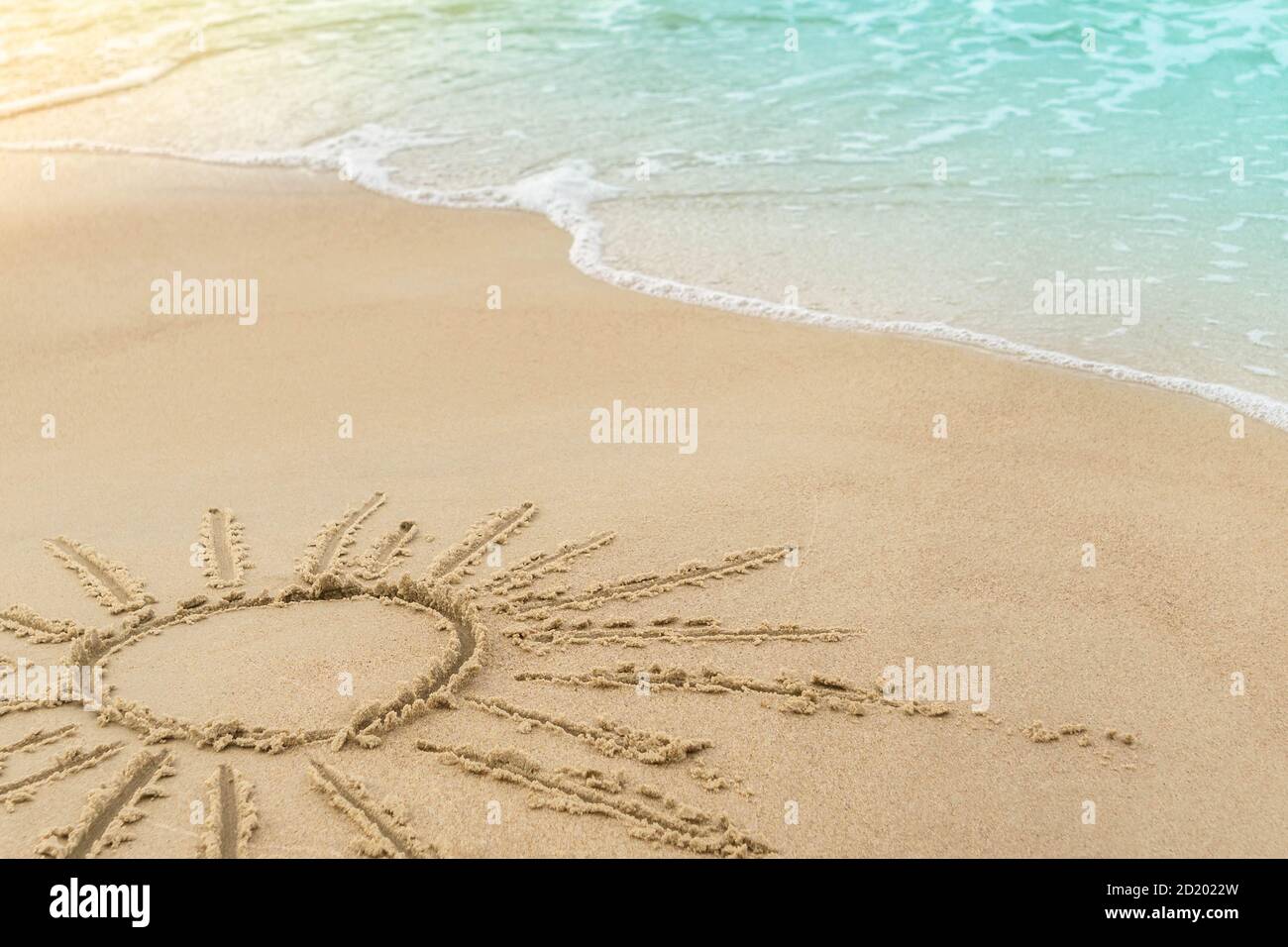 The sun symbol drawing on sand beach and wave with foam. Seashore ...