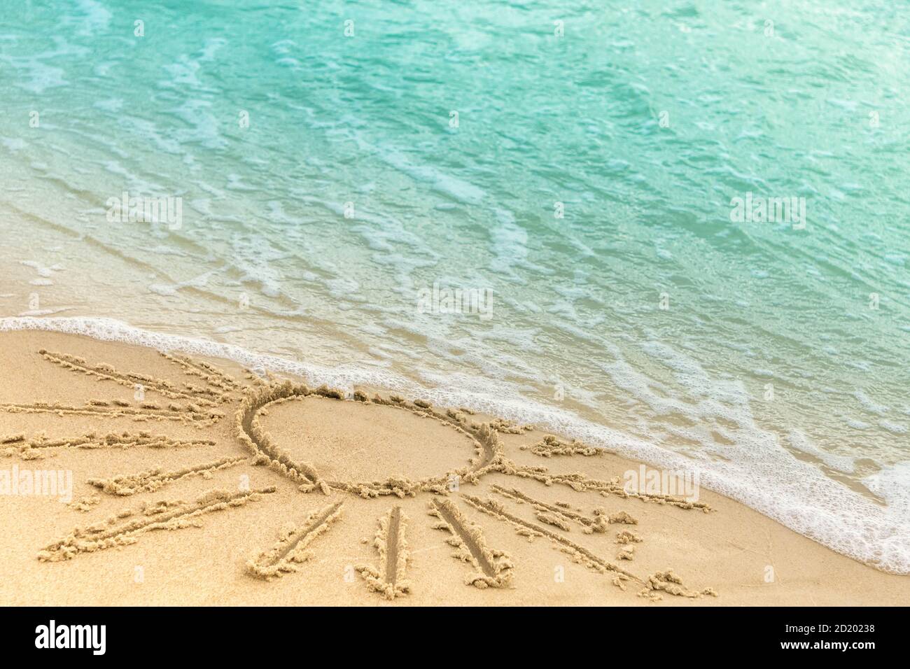 Sea wave covering symbol of the sun drawing on beach sand. Seashore ...