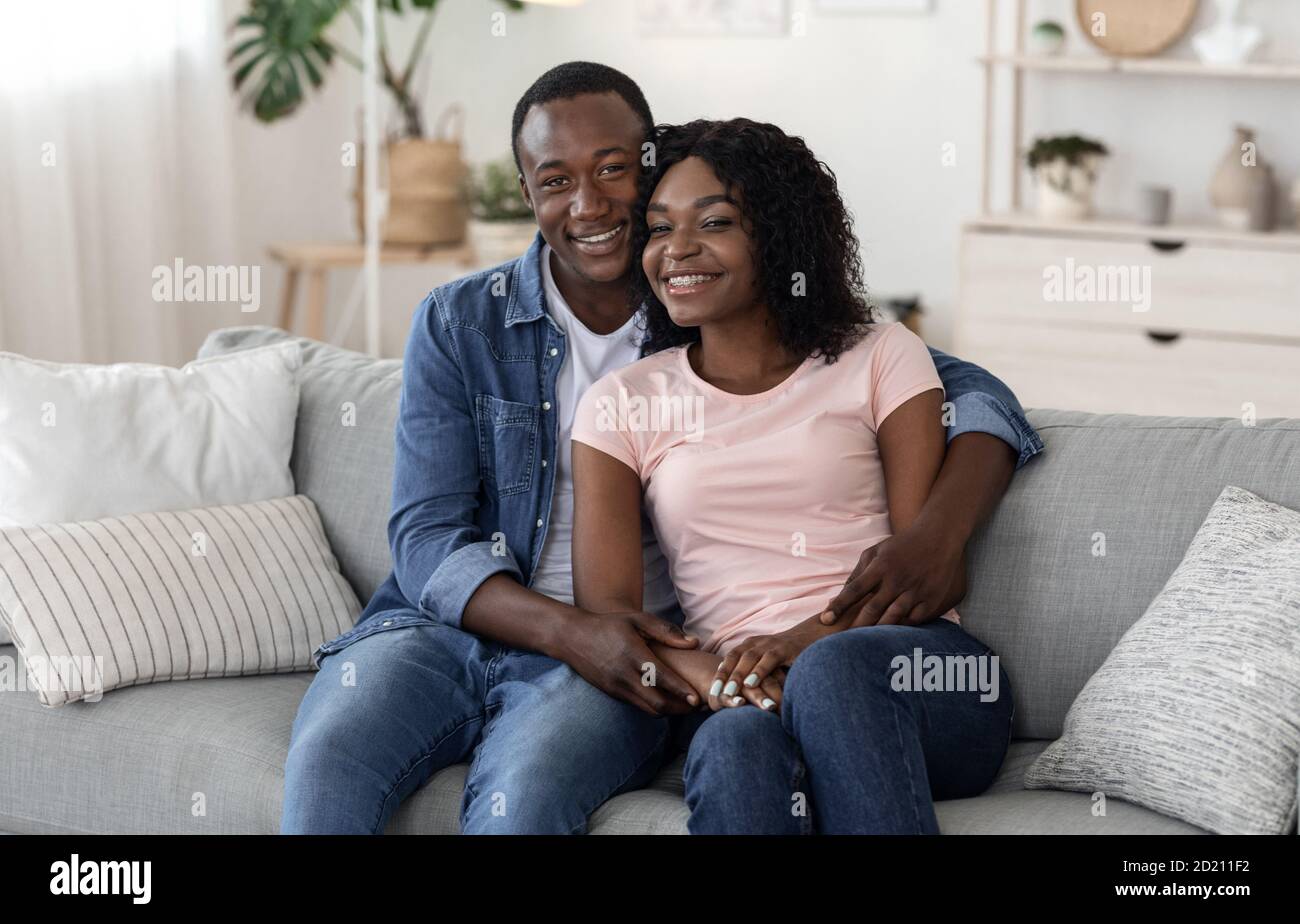 Happy african american couple cuddling on sofa at home Stock Photo - Alamy