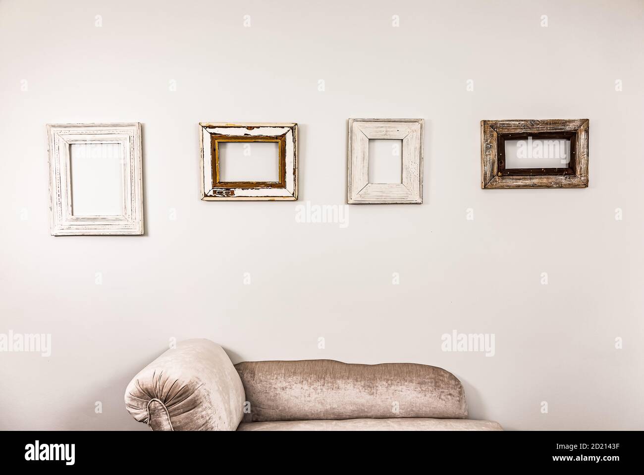 Empty wooden picture frames on a plain white wall for decor purposes ...