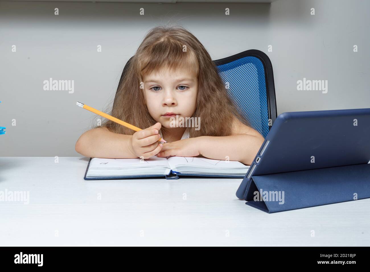 cute little girl in an online lesson on remote learning. the child is ...