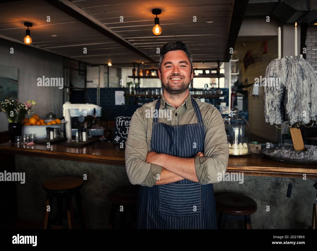 Smiling waiter standing with cross-arms happily working in cafe Stock ...