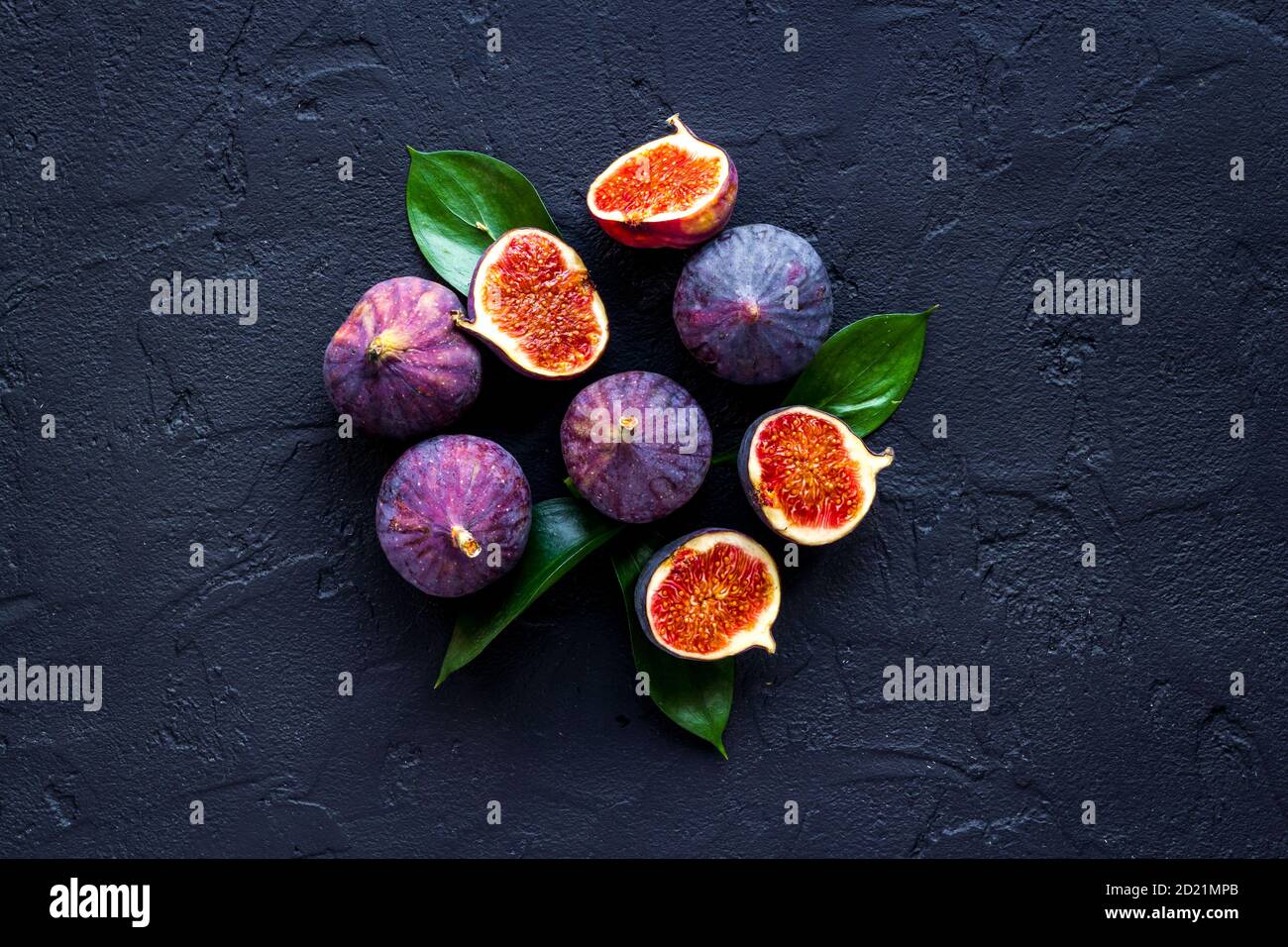 Tasty fresh figs cut in half with leaves, top view Stock Photo - Alamy