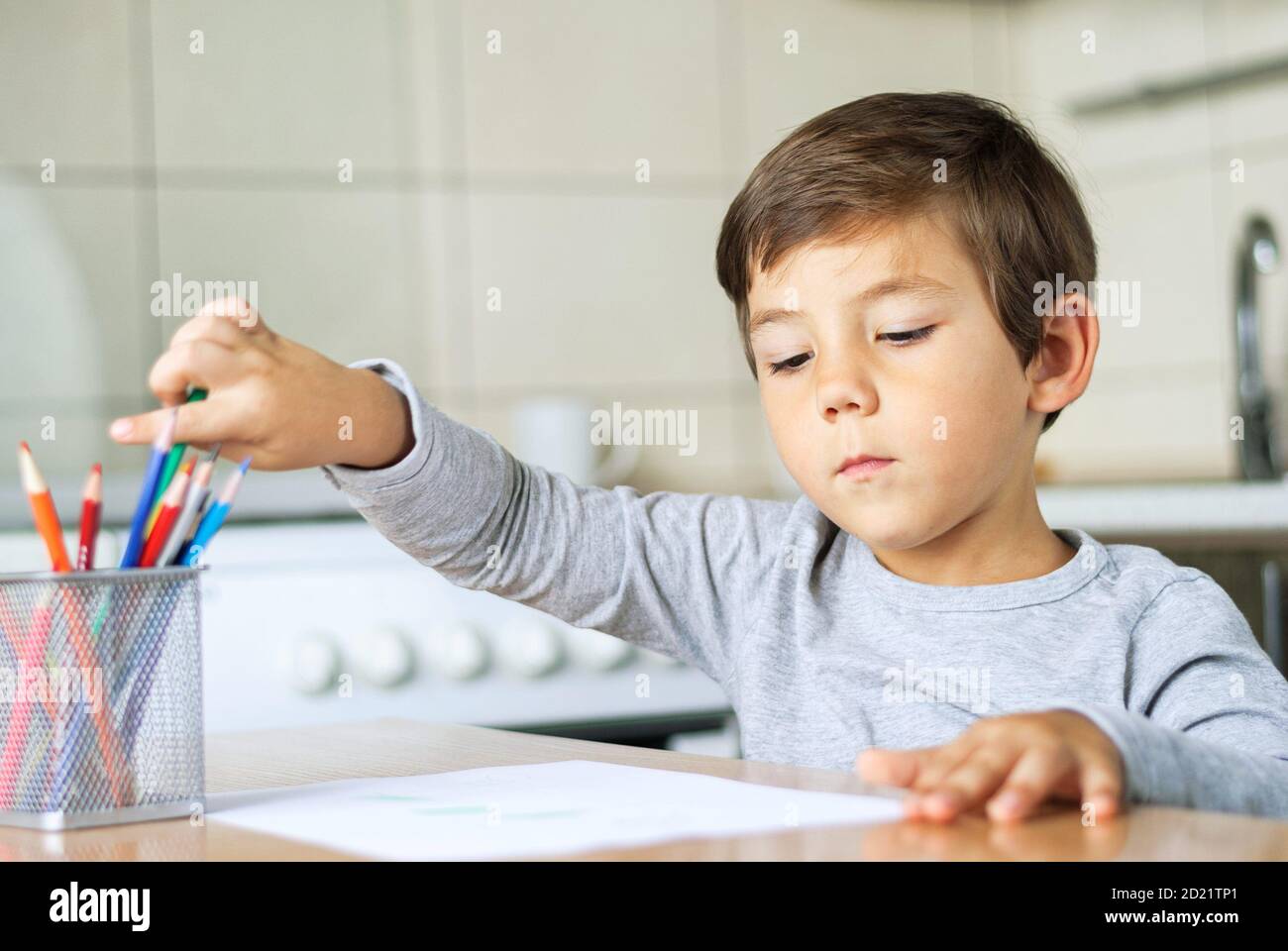 The boy takes a pencil in his hand to draw children's drawings on paper ...