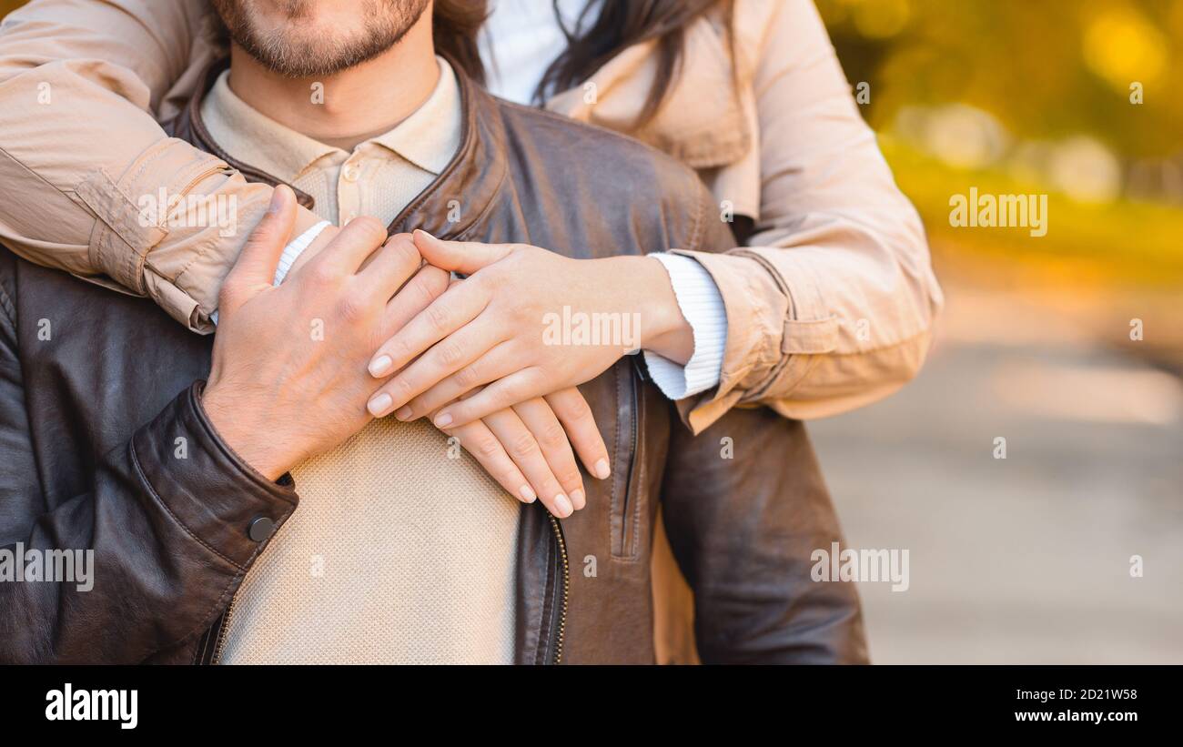 Woman hands hugging her boyfriend from behind, blurred park background ...
