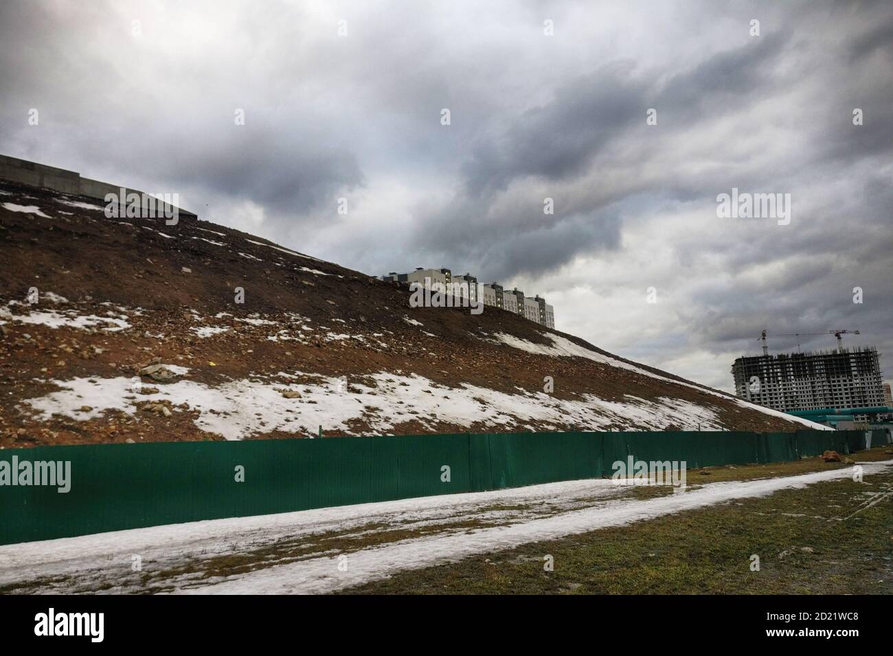 Dirty hill of the old landfill and new homes. Dump covered with earth ...