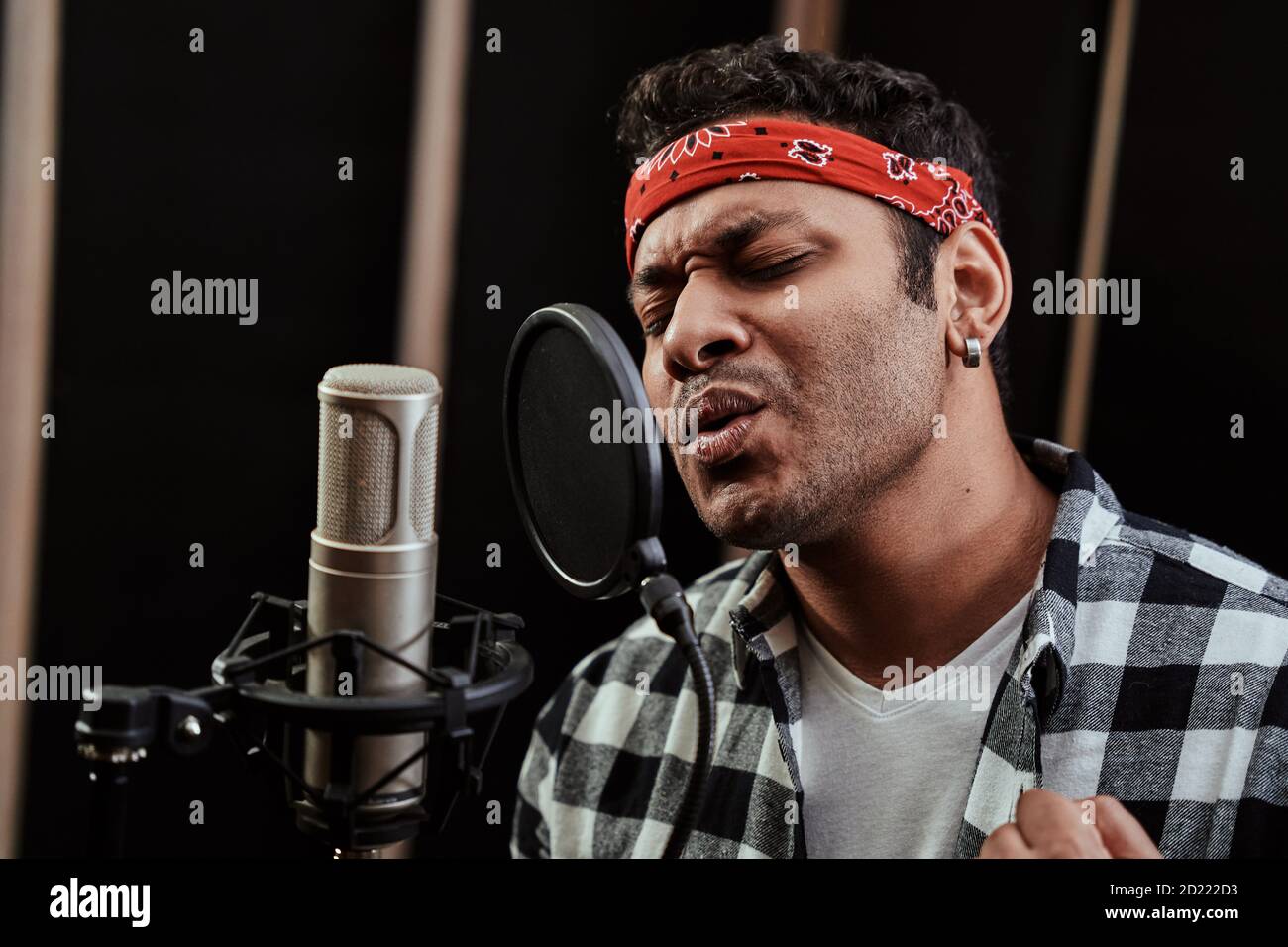 Portrait of young man, hip hop artist looking focused, singing into a ...