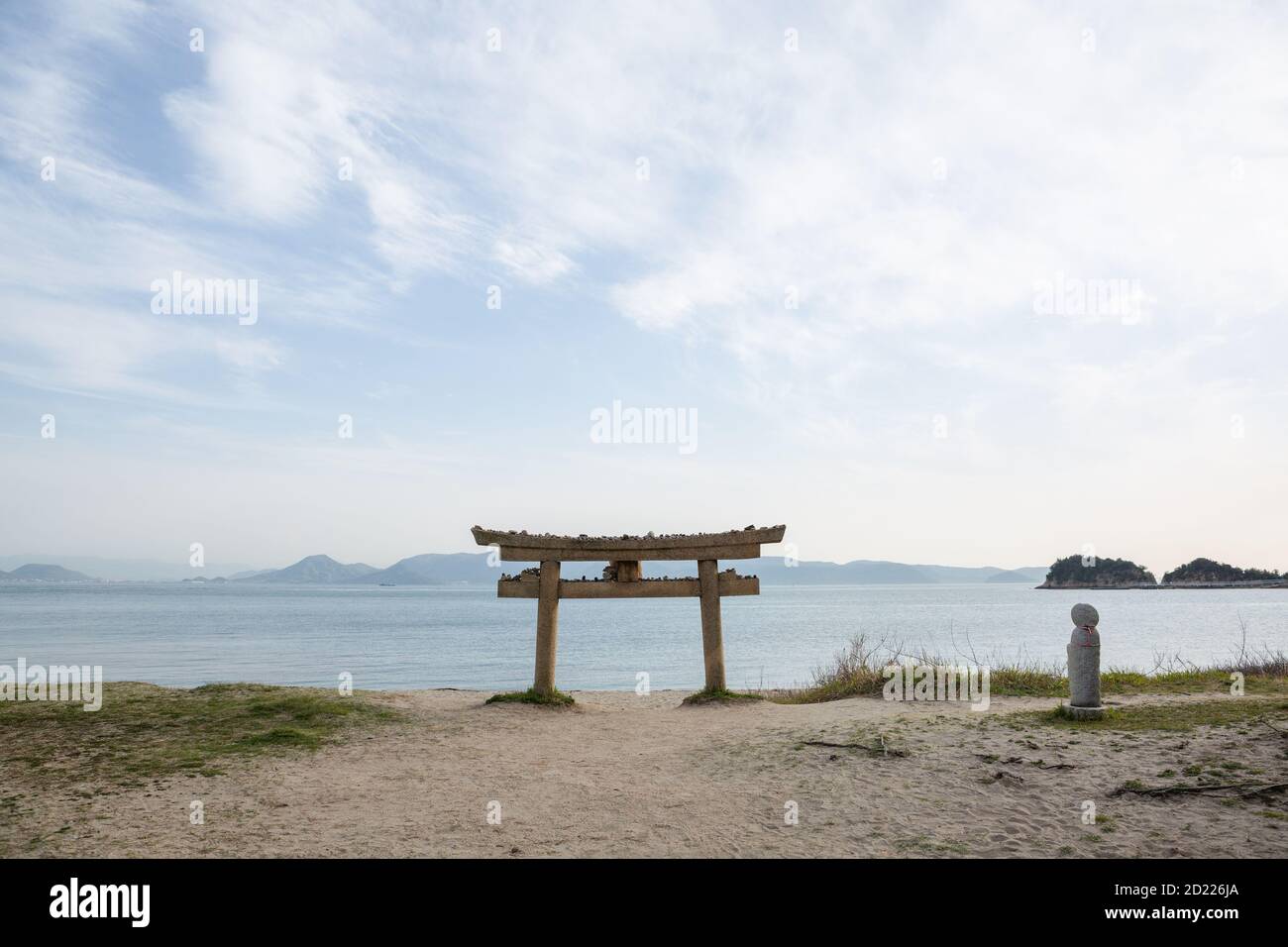 Torii on the beach with sea and islands visible behind, and stones ...