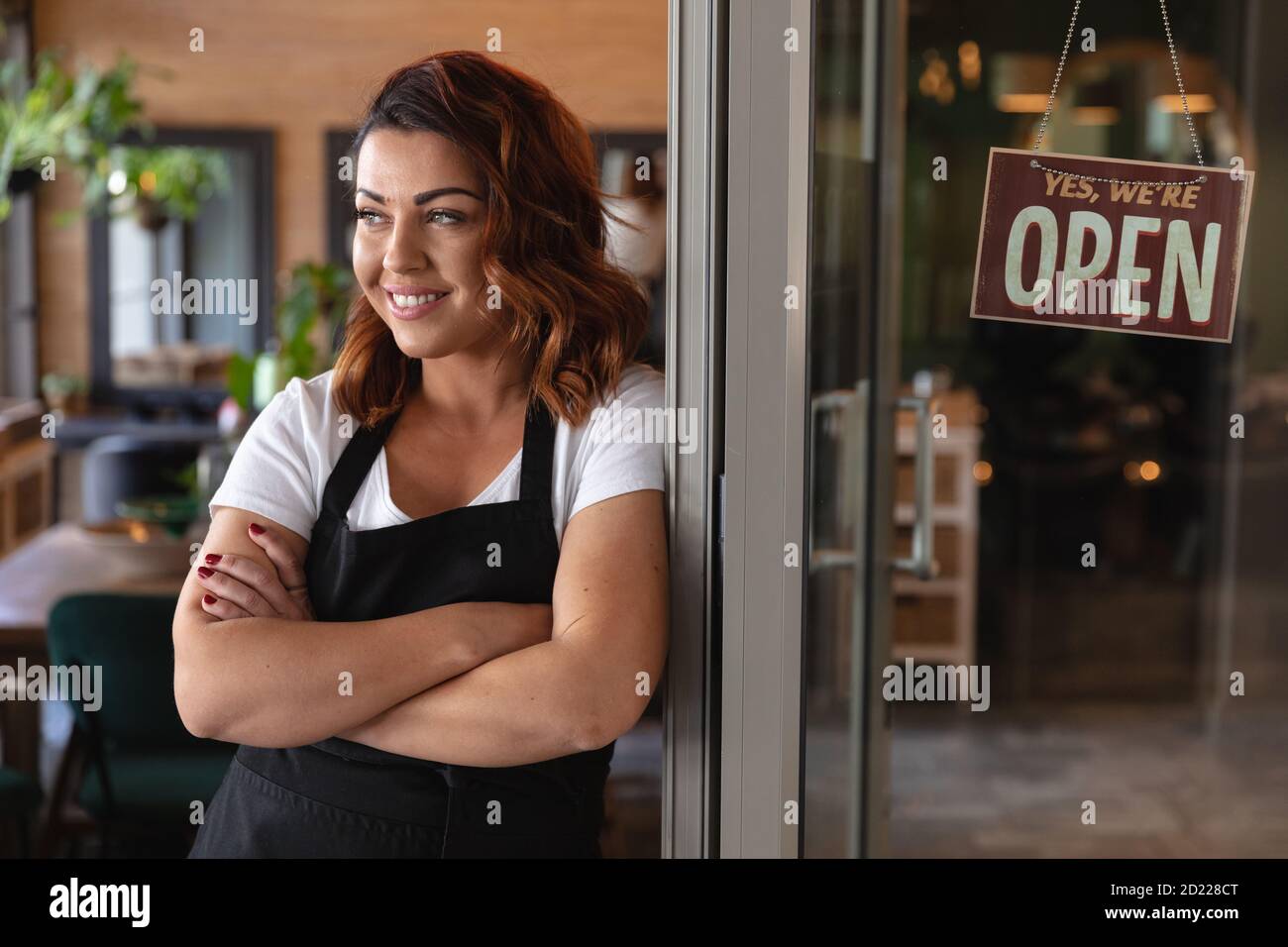 Female hairdresser leaning on the glass door at hair salon Stock Photo ...