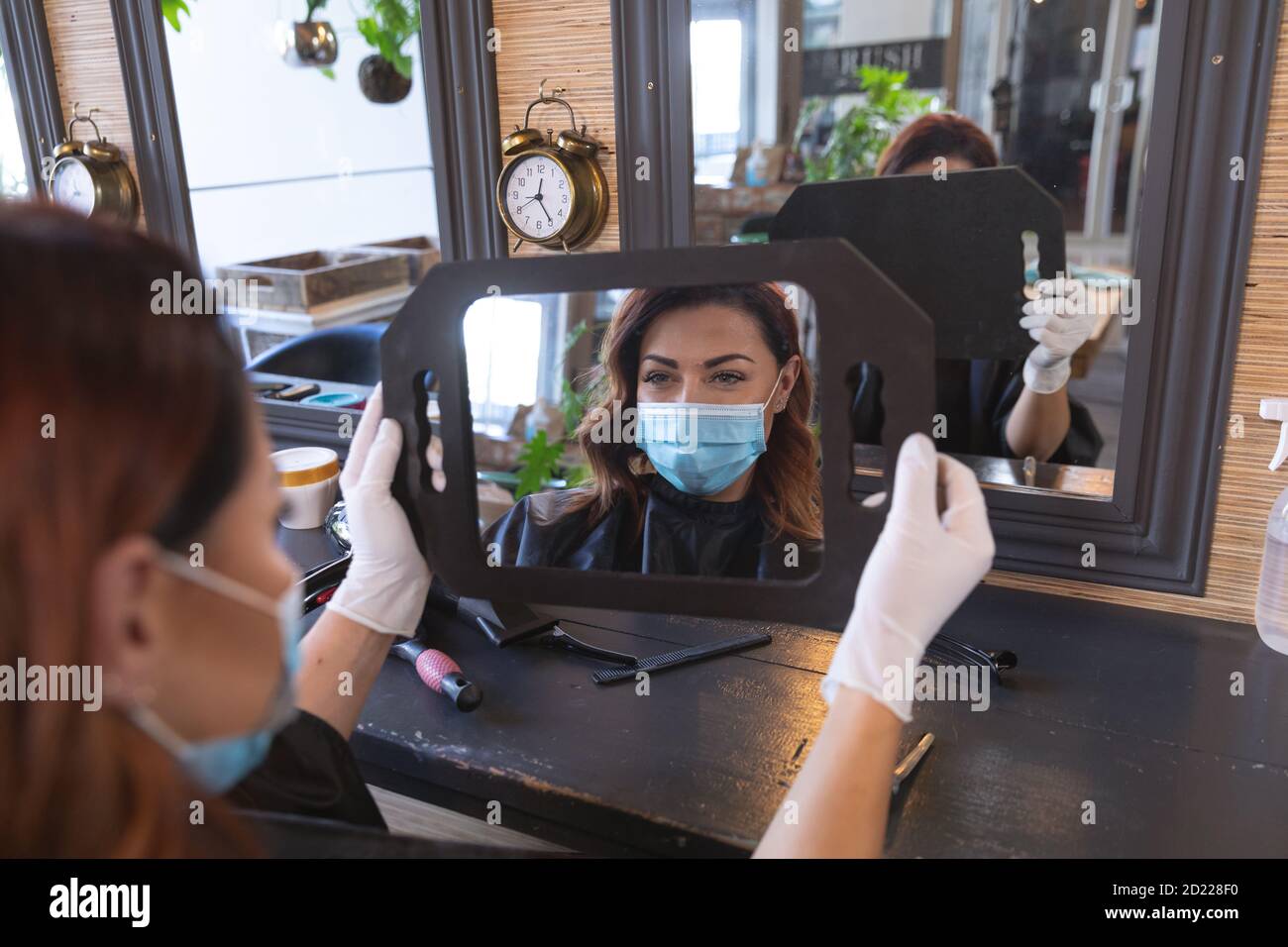 Female customer wearing face mask looking at her reflection in the ...