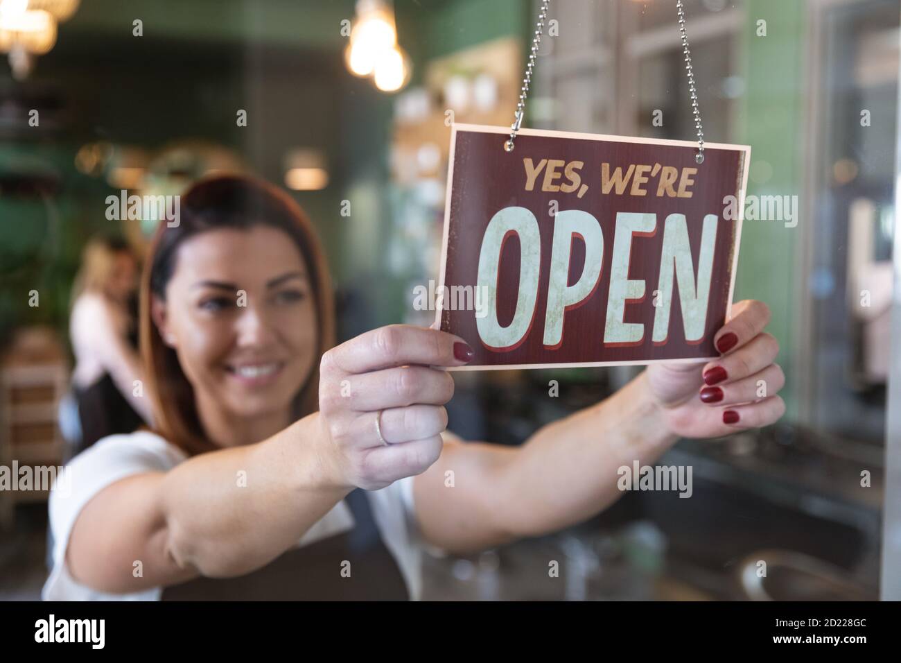 Female hairdresser holding Open sign board at hair salon Stock Photo ...