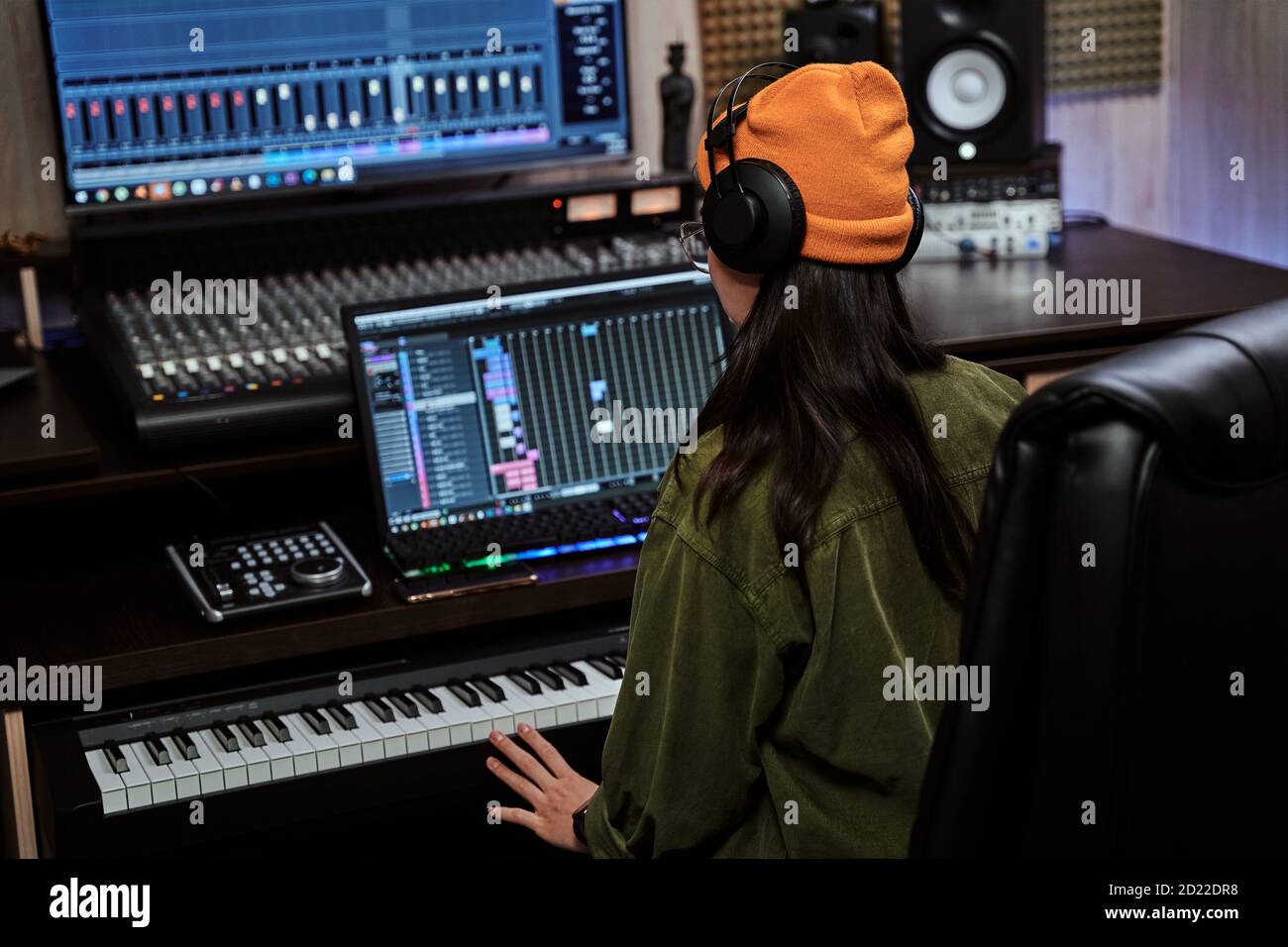 Young woman, female artist looking focused while playing keyboard ...