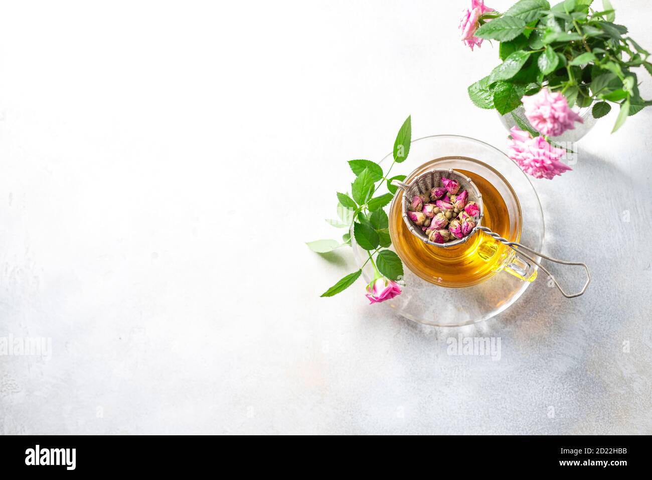 Pink tea buds, a glass cup and vintage strainer Stock Photo - Alamy
