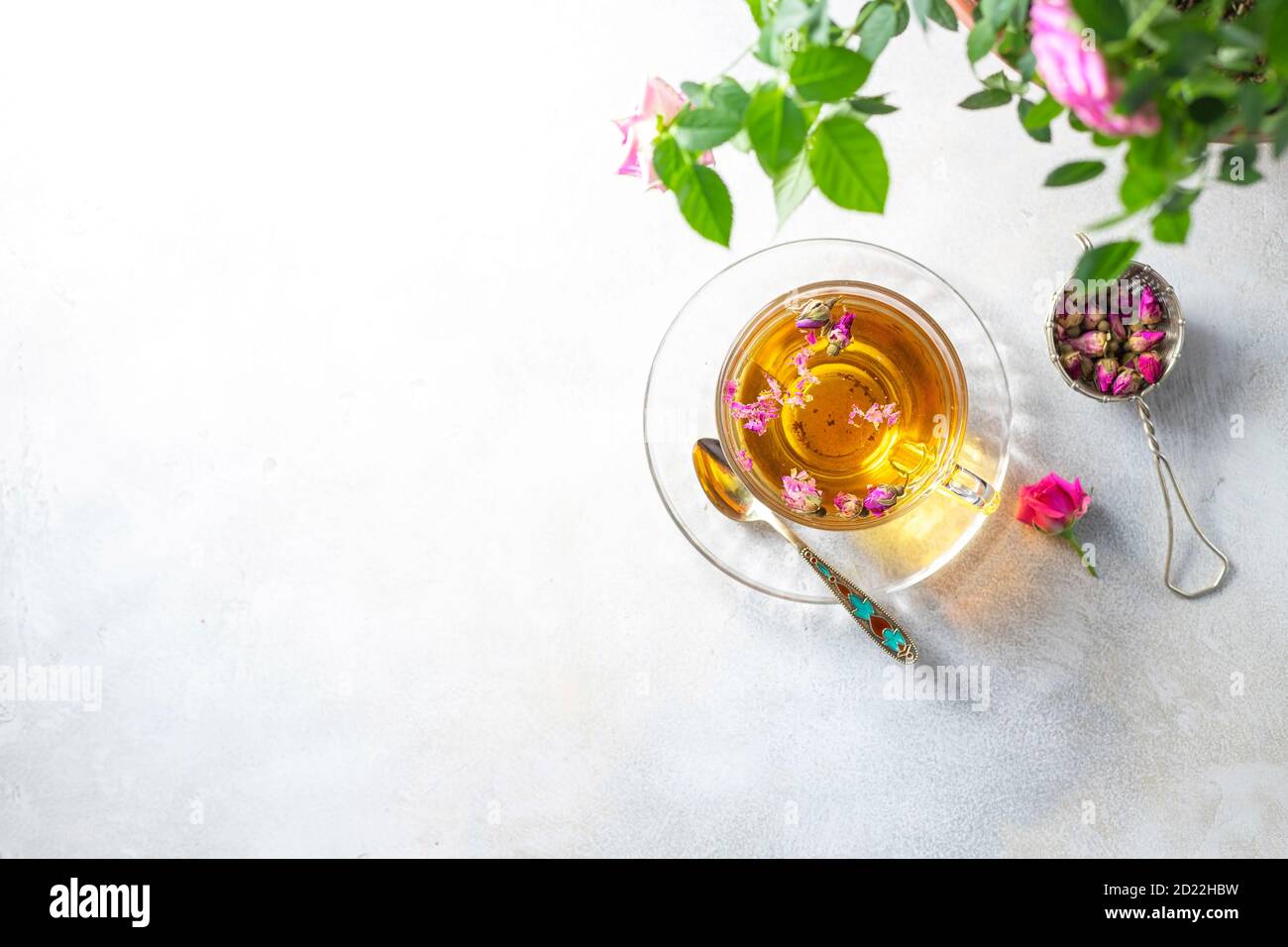 Pink tea buds, a glass cup and vintage strainer Stock Photo - Alamy