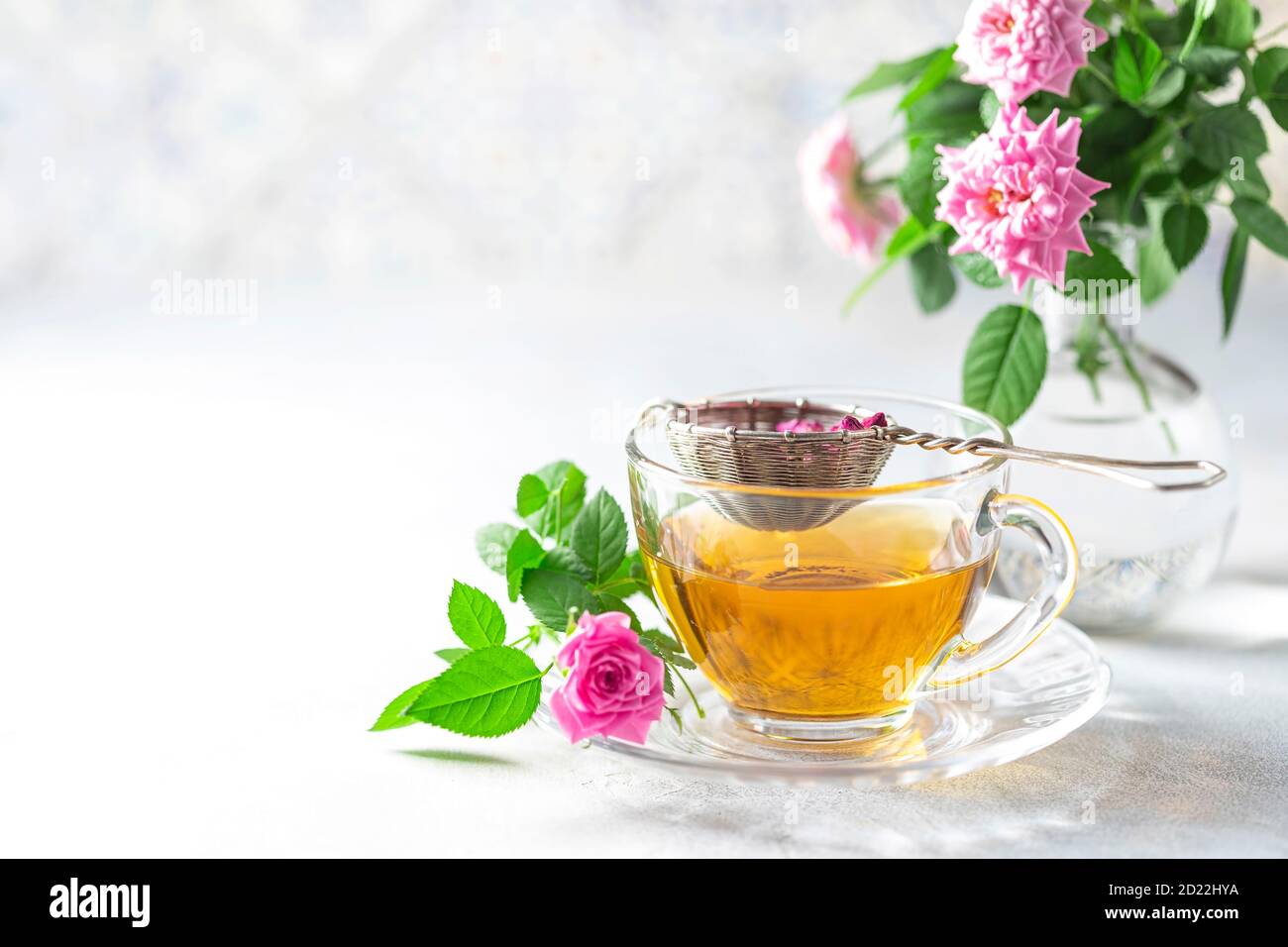 Pink tea buds, a glass cup and vintage strainer Stock Photo - Alamy