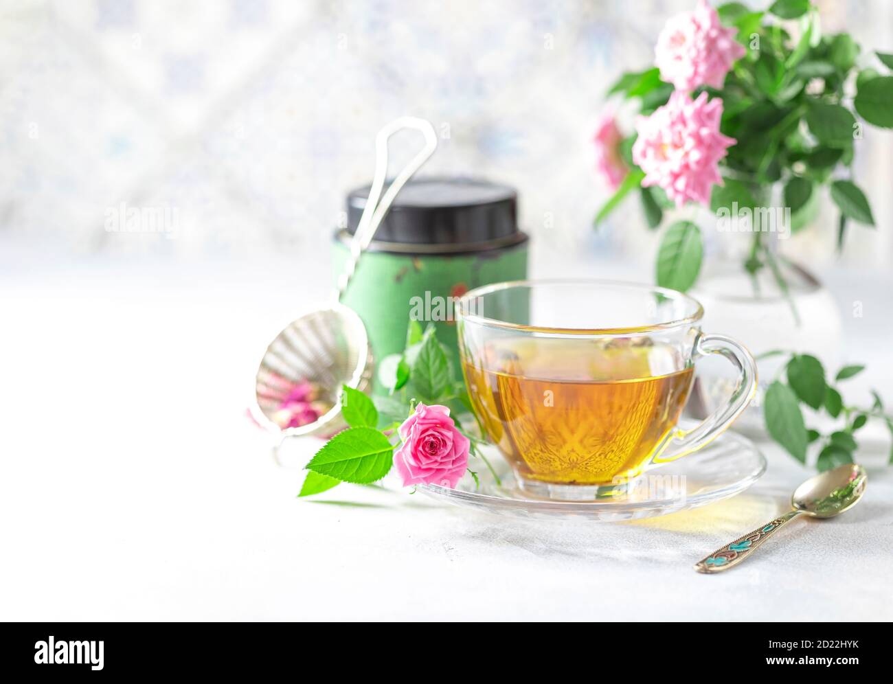 Pink tea buds, a glass cup and vintage strainer Stock Photo - Alamy