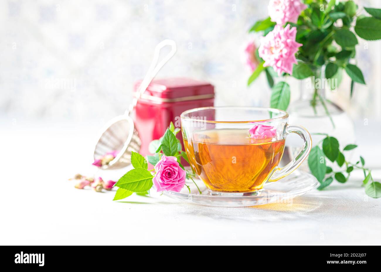 Pink tea buds, a glass cup and vintage strainer Stock Photo - Alamy