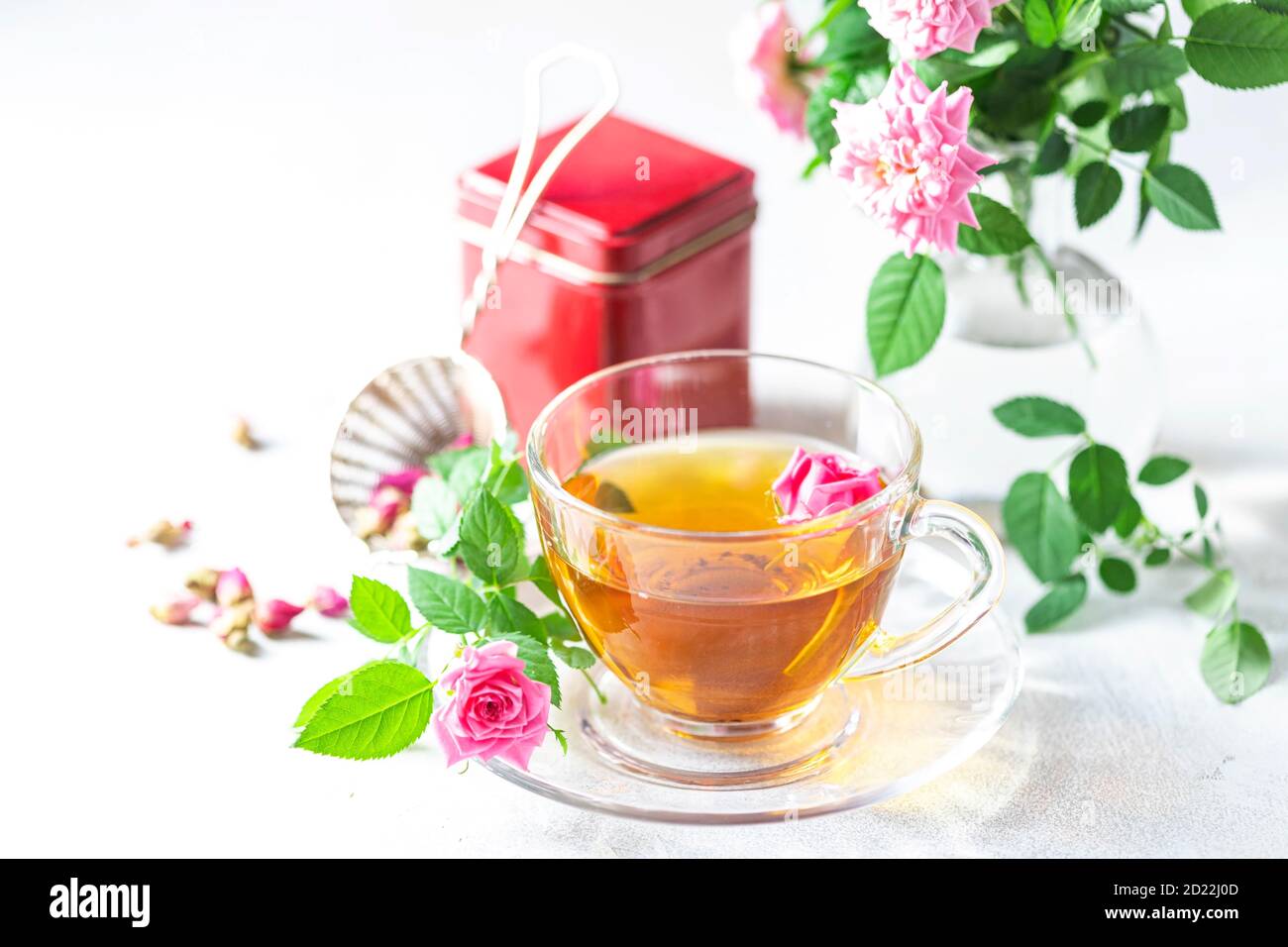 Pink tea buds, a glass cup and vintage strainer Stock Photo - Alamy