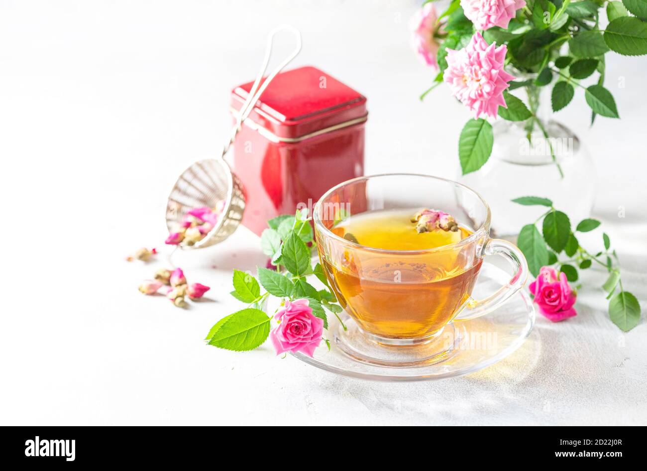 Pink tea buds, a glass cup and vintage strainer Stock Photo - Alamy