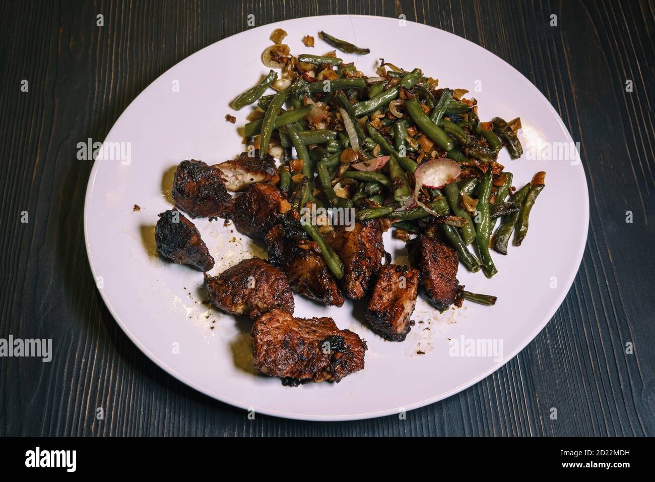 Plate with burnt overcooked meat and garnish on dark background Stock ...