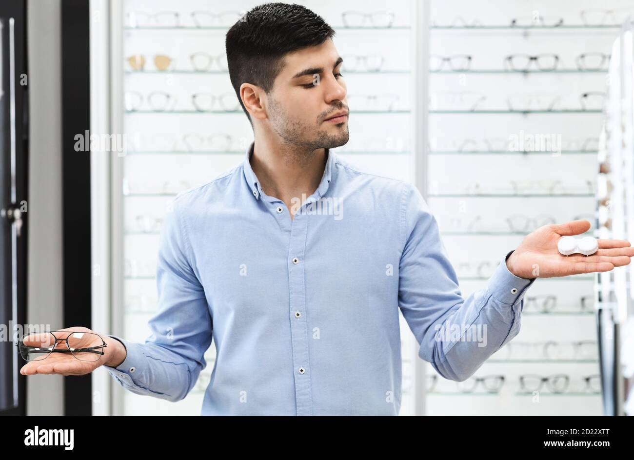 Pensive guy choosing between eyeglasses and contacts Stock Photo - Alamy