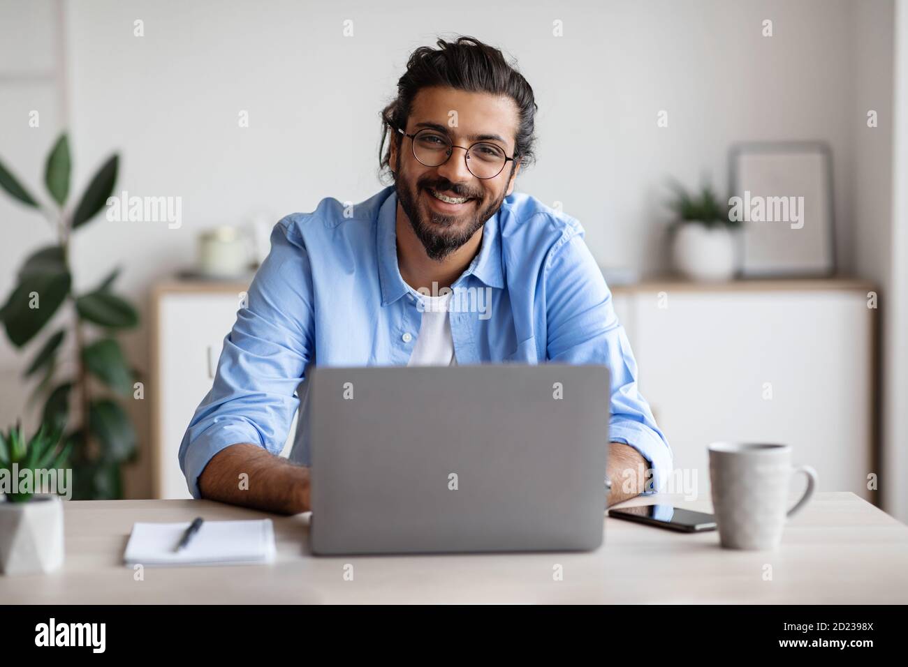 Happy Indian Freelancer Man Sitting At Desk With Laptop, Smiling At ...