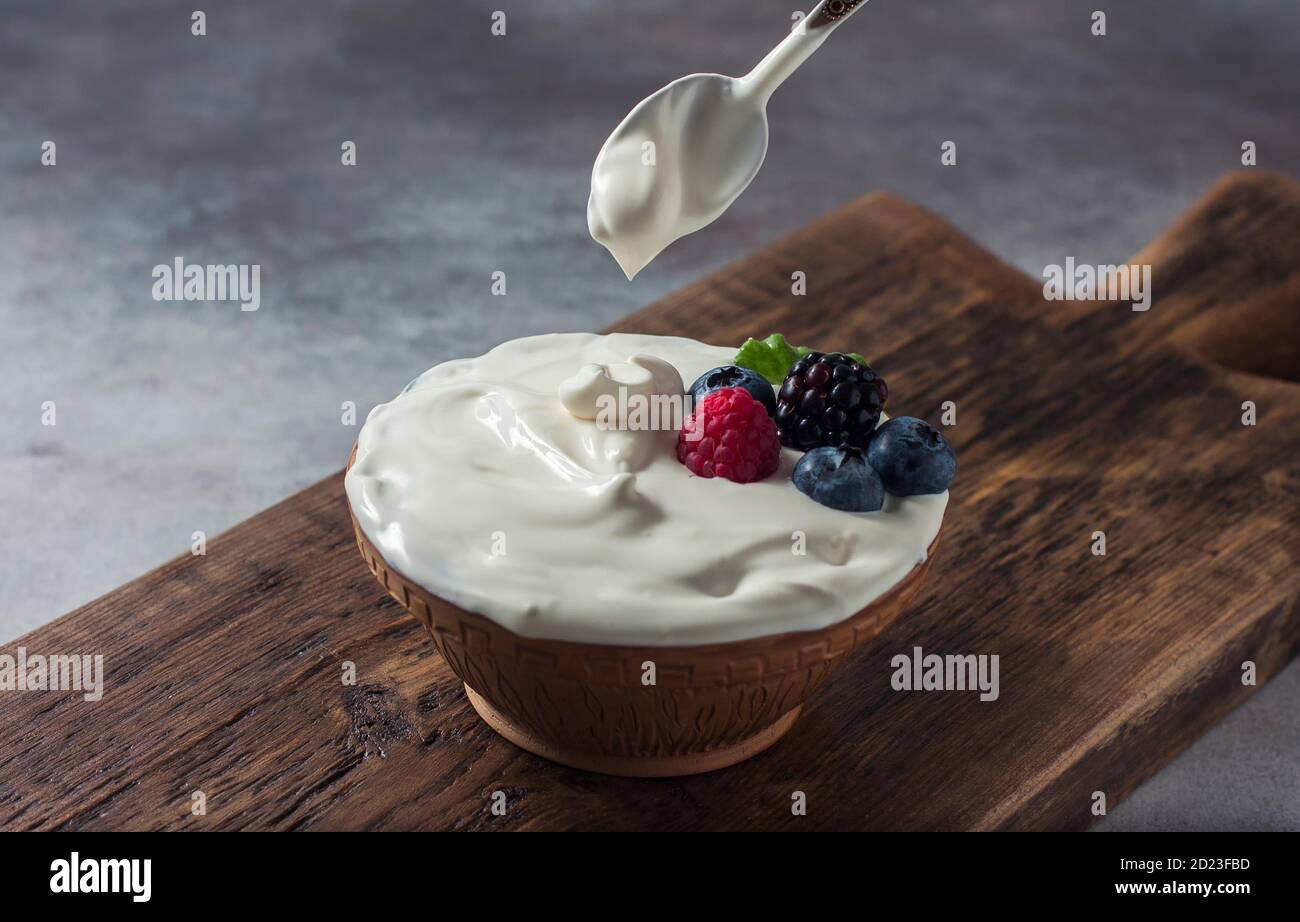 Greek yogurt in a wooden bowl on a rustic wooden table Stock Photo - Alamy