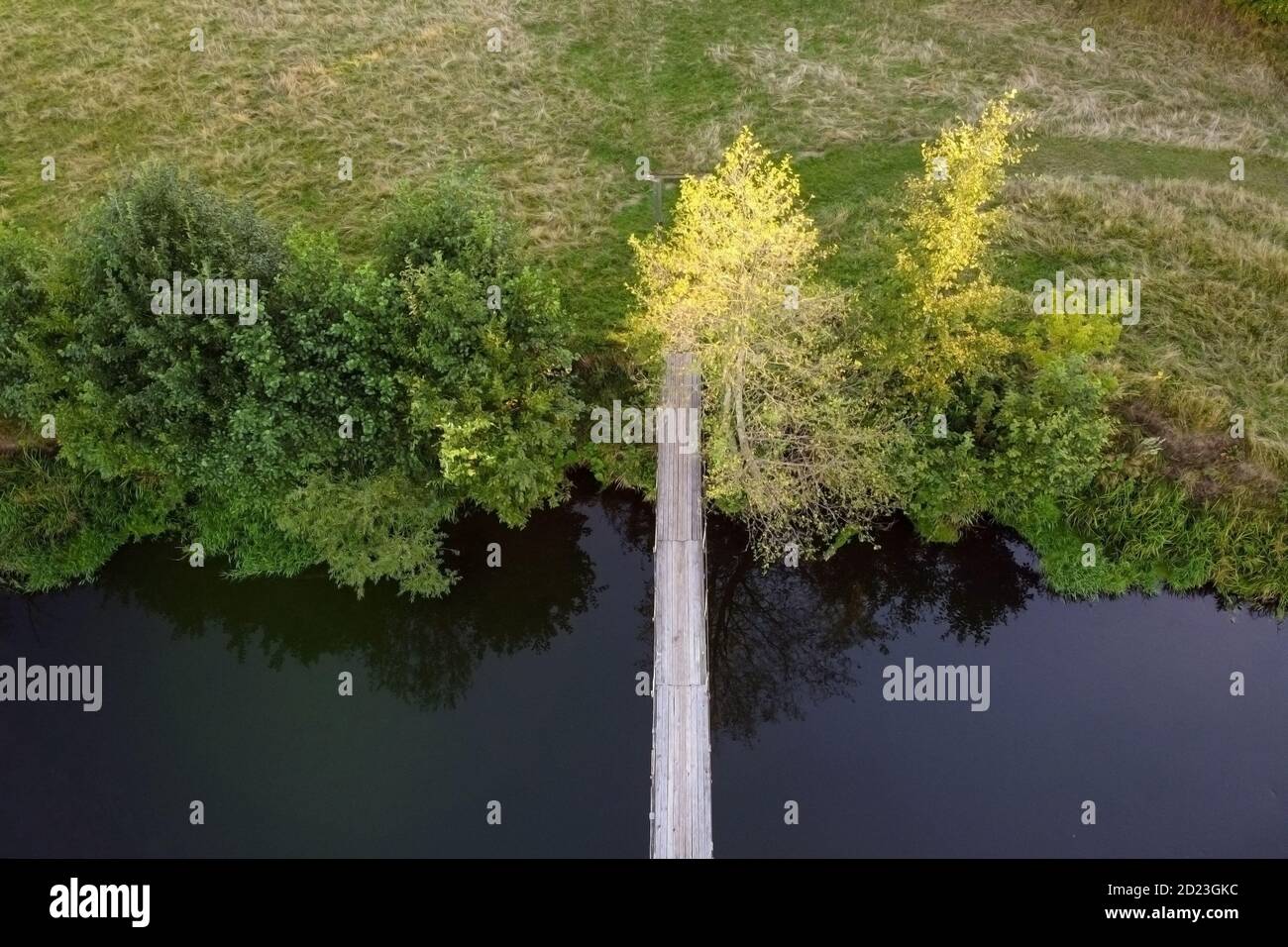 Aerial view of a simple suspension bridge over a small river. Summer ...