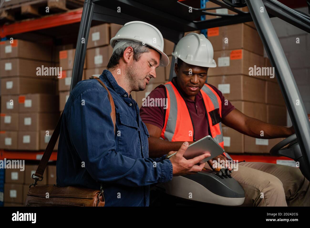 Two male workers wearing hard hats holding digital tablet researching ...