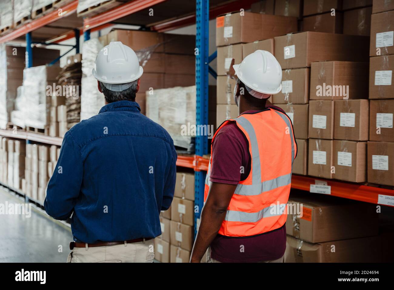 Caucasian businessman and ethnic factory worker walking through ...