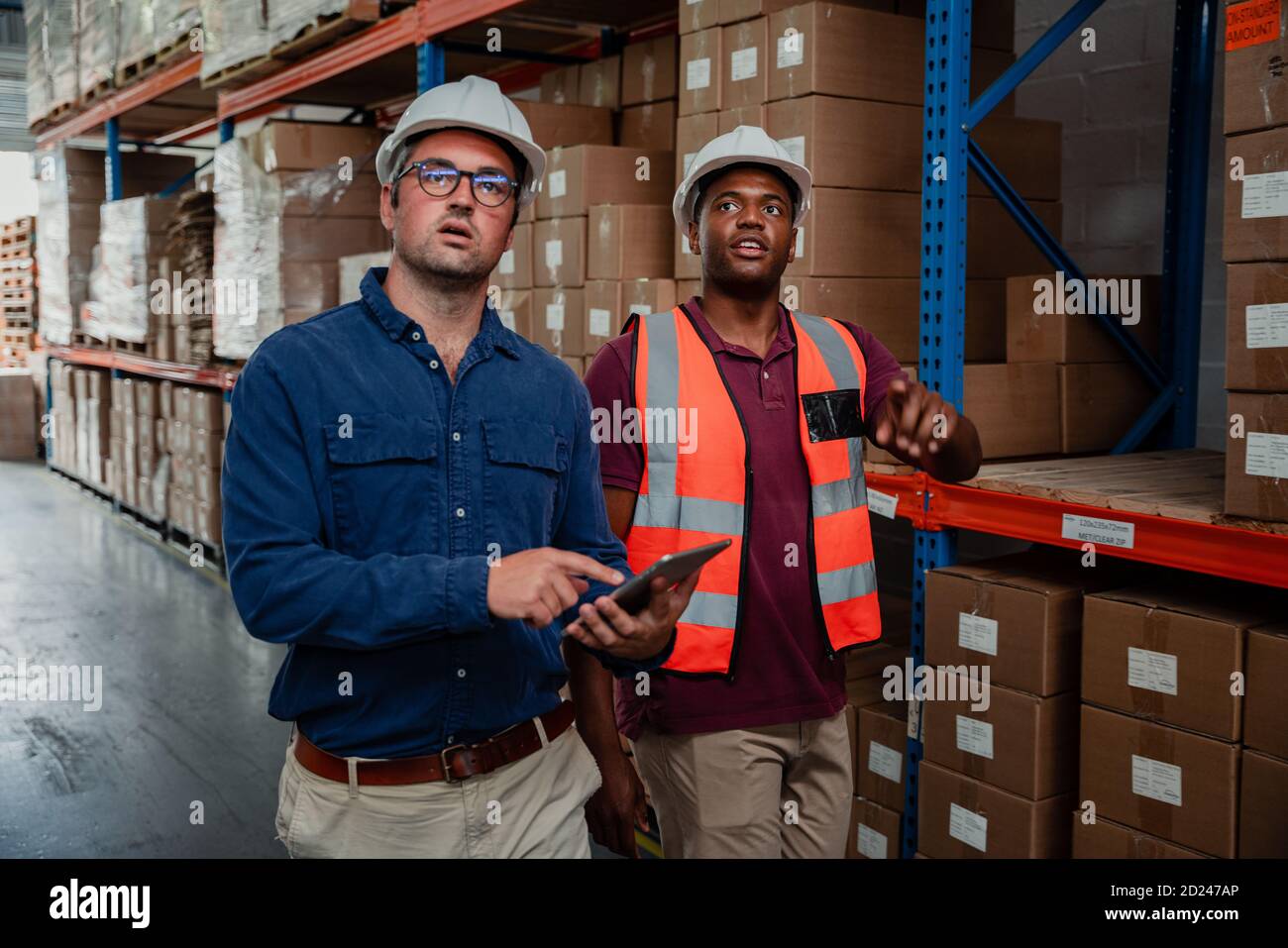 Businessman wearing glasses holding digital tablet while factory worker ...