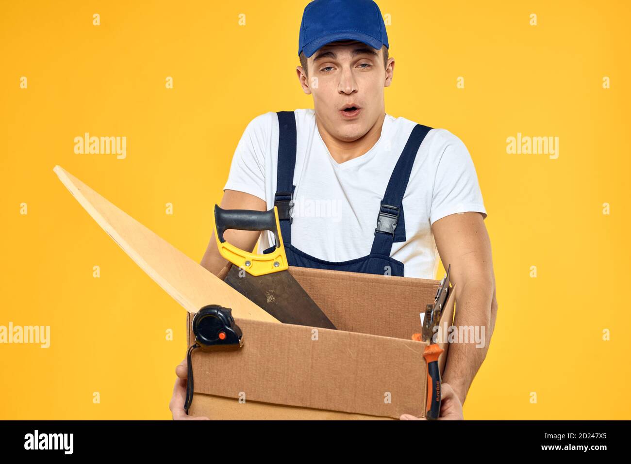 worker with box in hand tools loader yellow background Stock Photo - Alamy