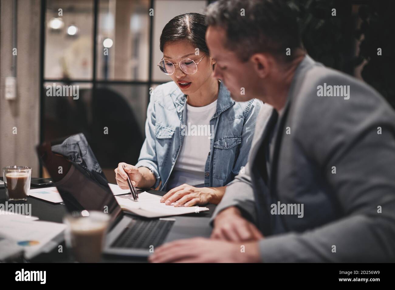 Two diverse businesspeople going over paperwork together while working ...